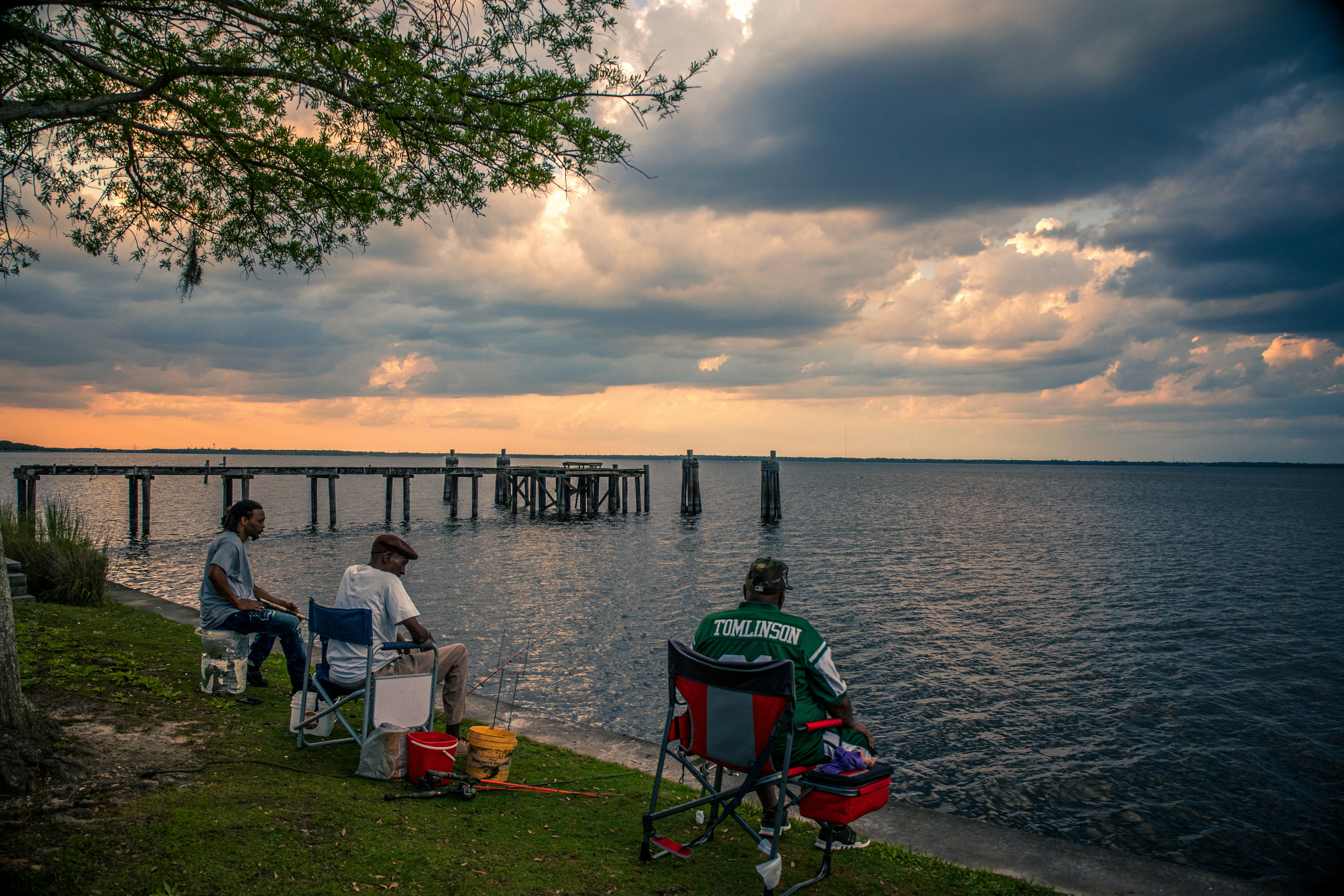 A couple of people sitting next to a body of water photo – Free Fl ...