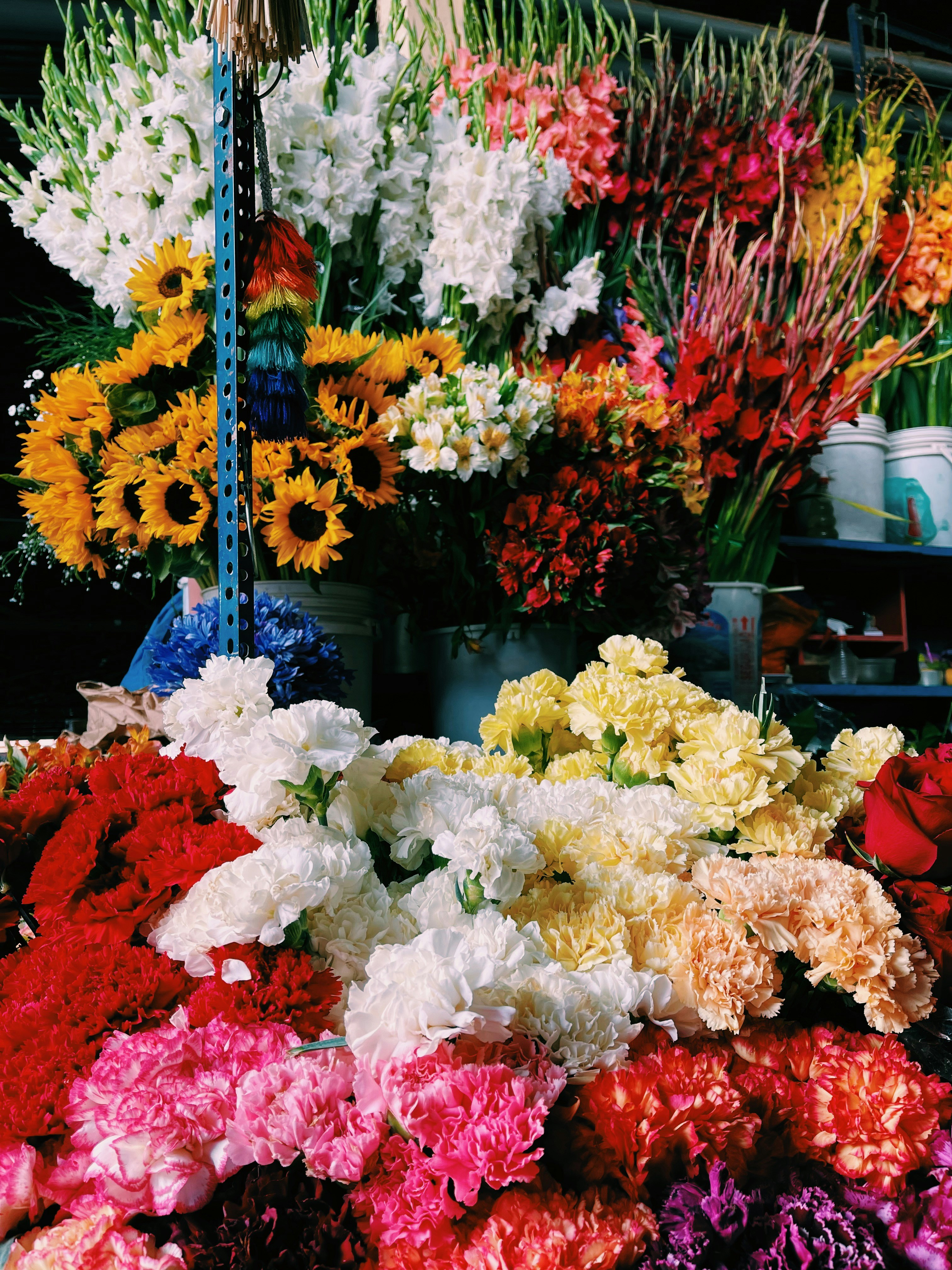 Vibrant array of flowers in a market, showcasing a rich tapestry of colors and textures. The display features various floral species arranged artistically.