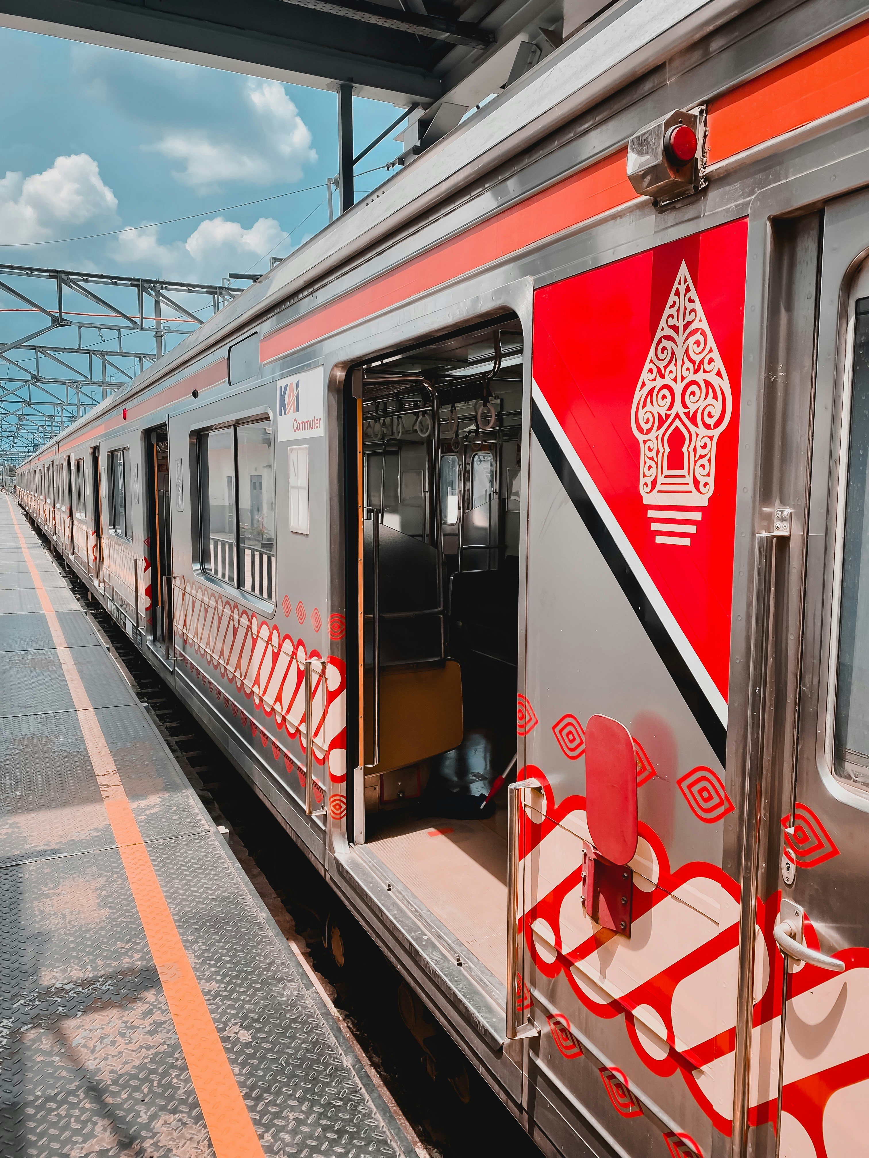A red and silver train stopped at a train station photo – Free Stasiun ...