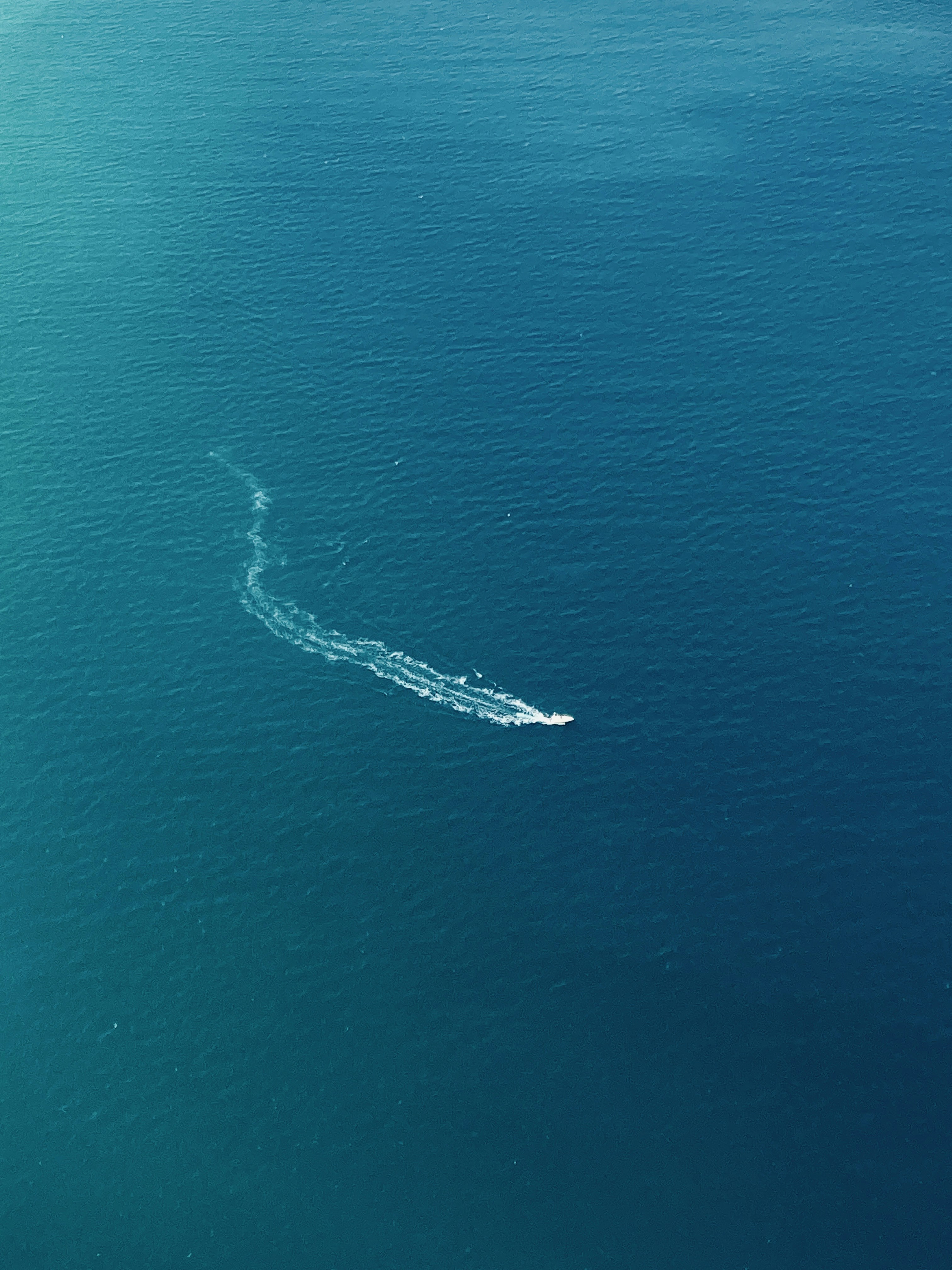 A speedboat leaves a white wake as it glides across deep blue ocean waters, capturing the essence of maritime exploration.