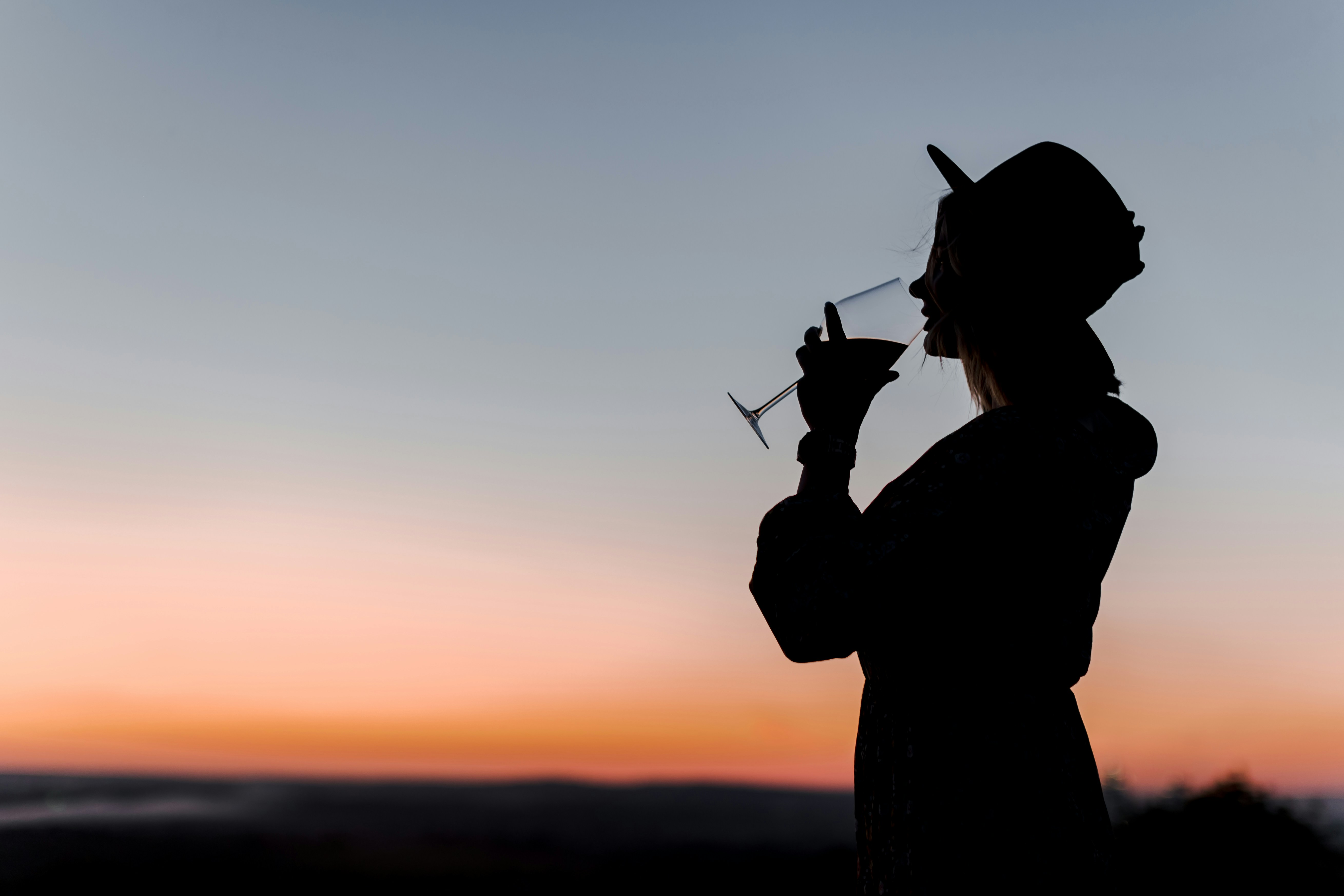 Woman with glass of wine on sunset. Space for text.