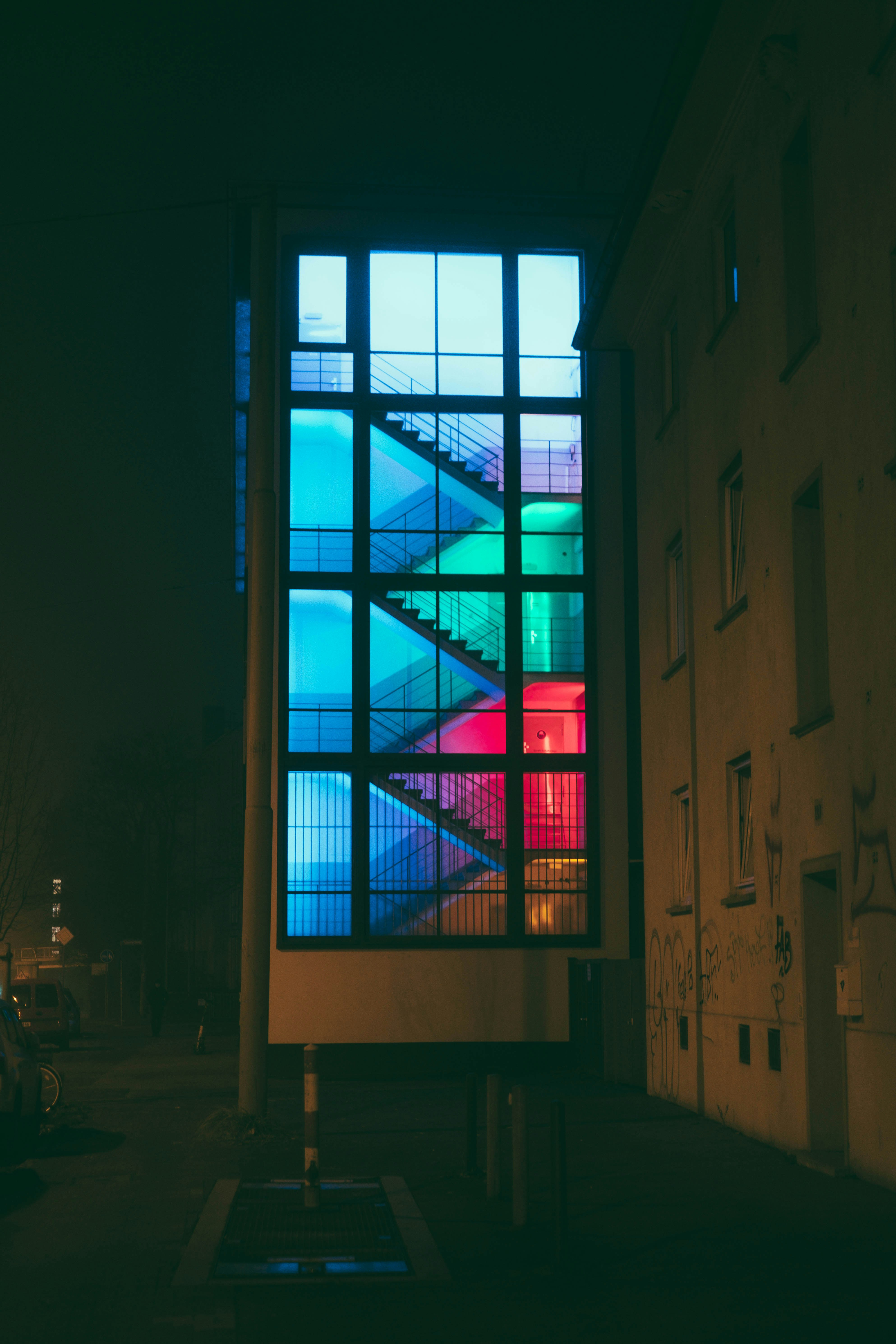 Chromatic Staircase Window: Neon Steps Through Urban Glass
