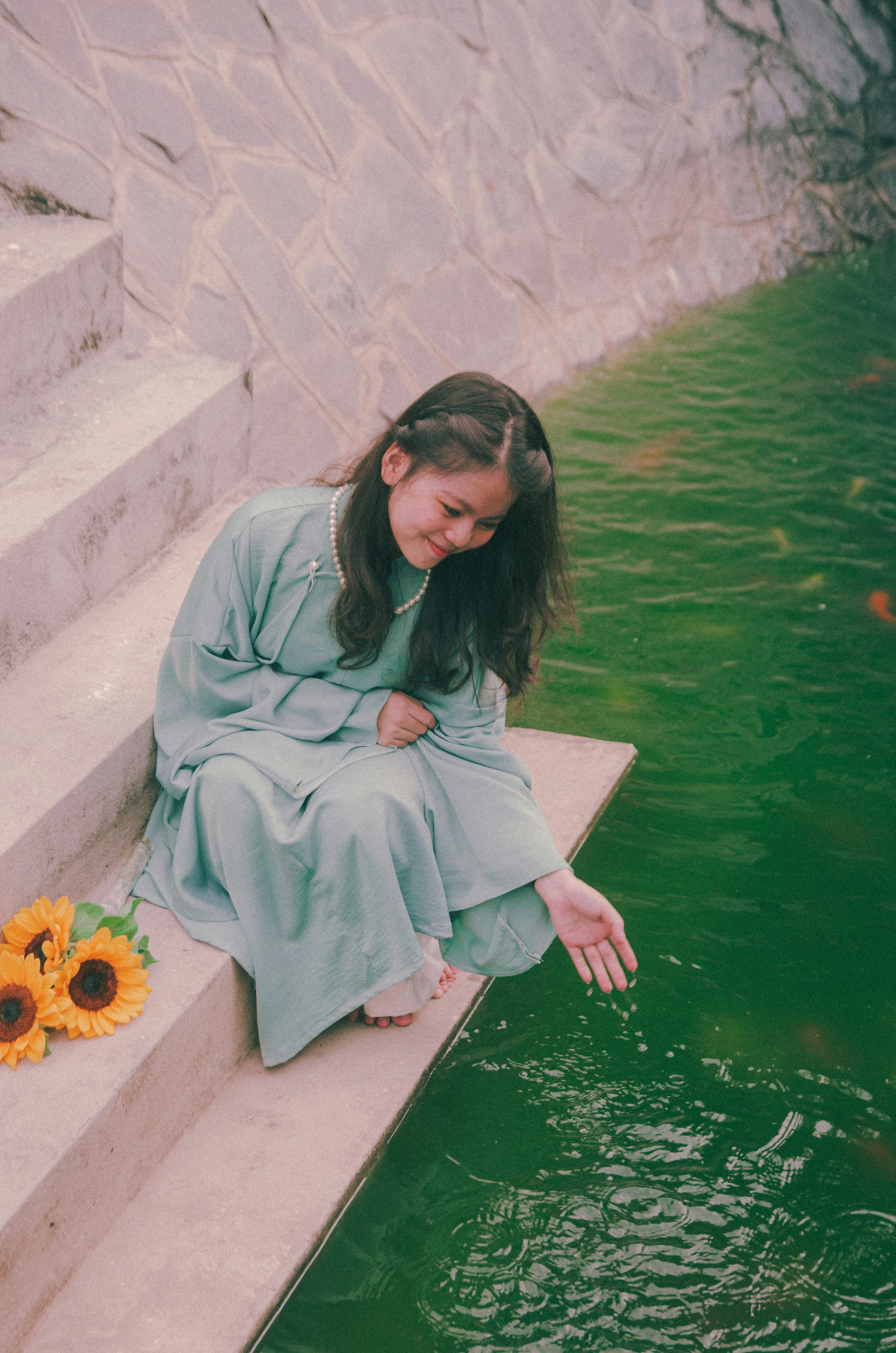 Girl in a pale blue dress testimonials by the water’s edge