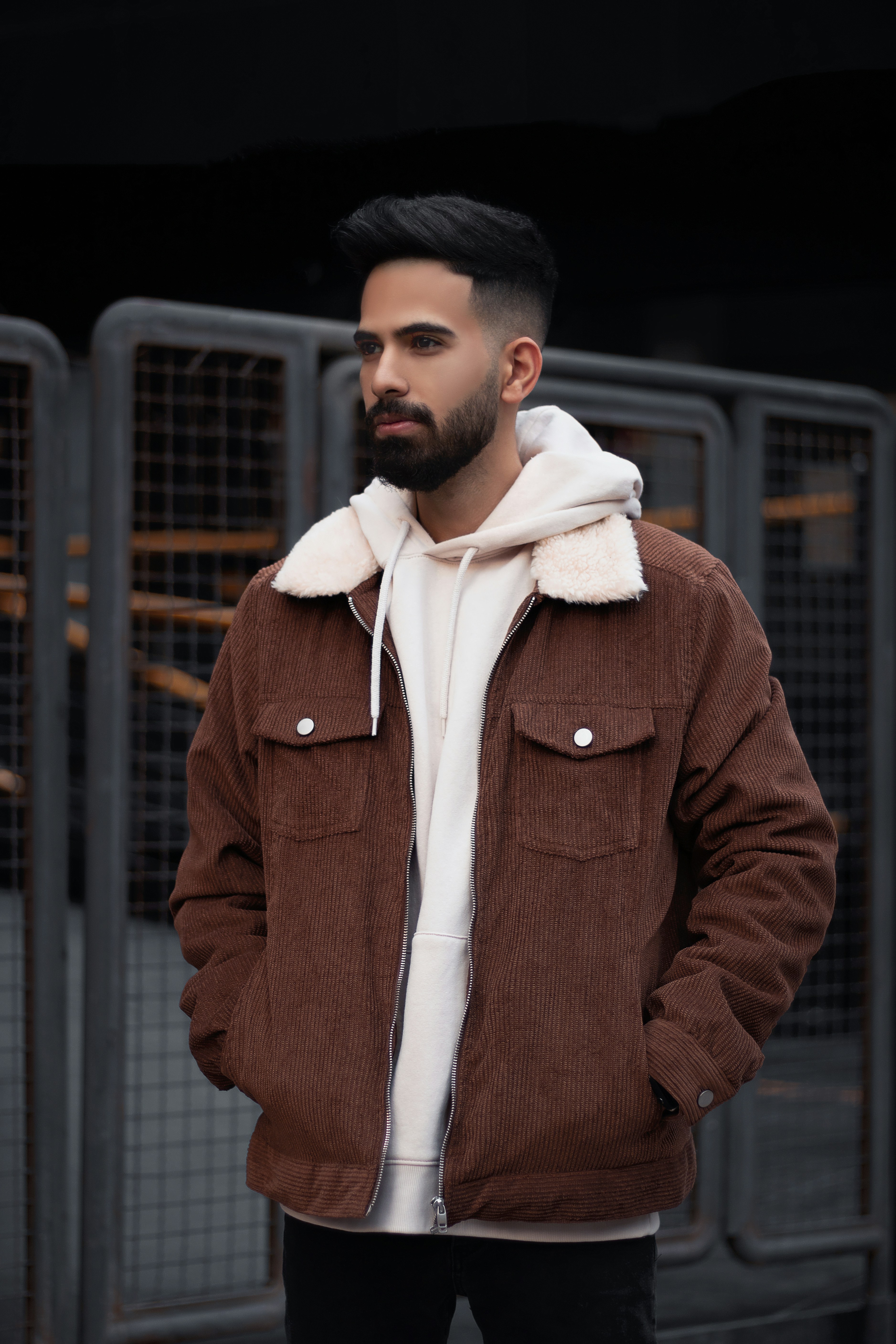 Corduroy Confidence: A Portrait Against Industrial Fencing