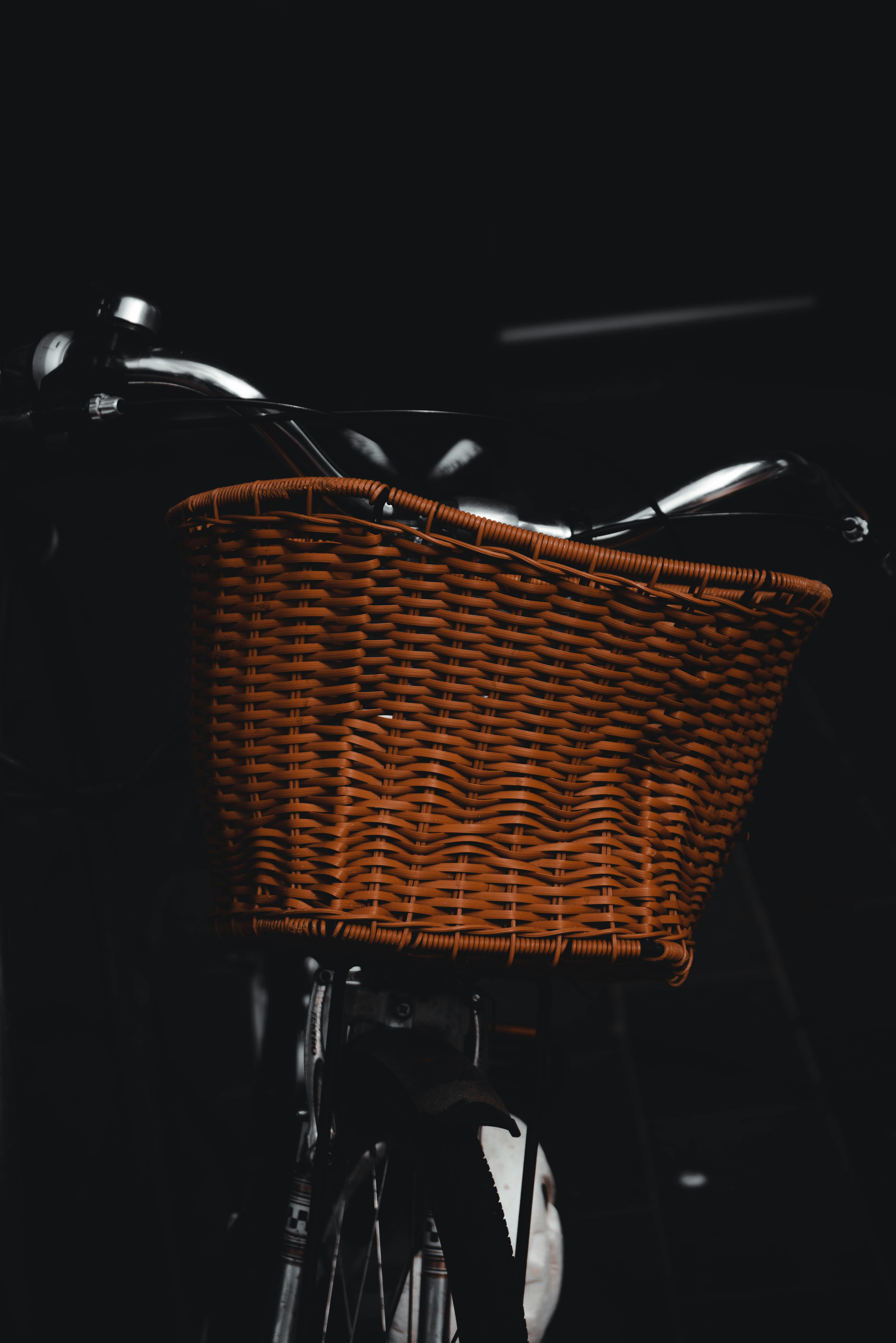 Close-up of a vintage bicycle's woven basket against a dark backdrop, highlighting its rustic charm and subtle details.