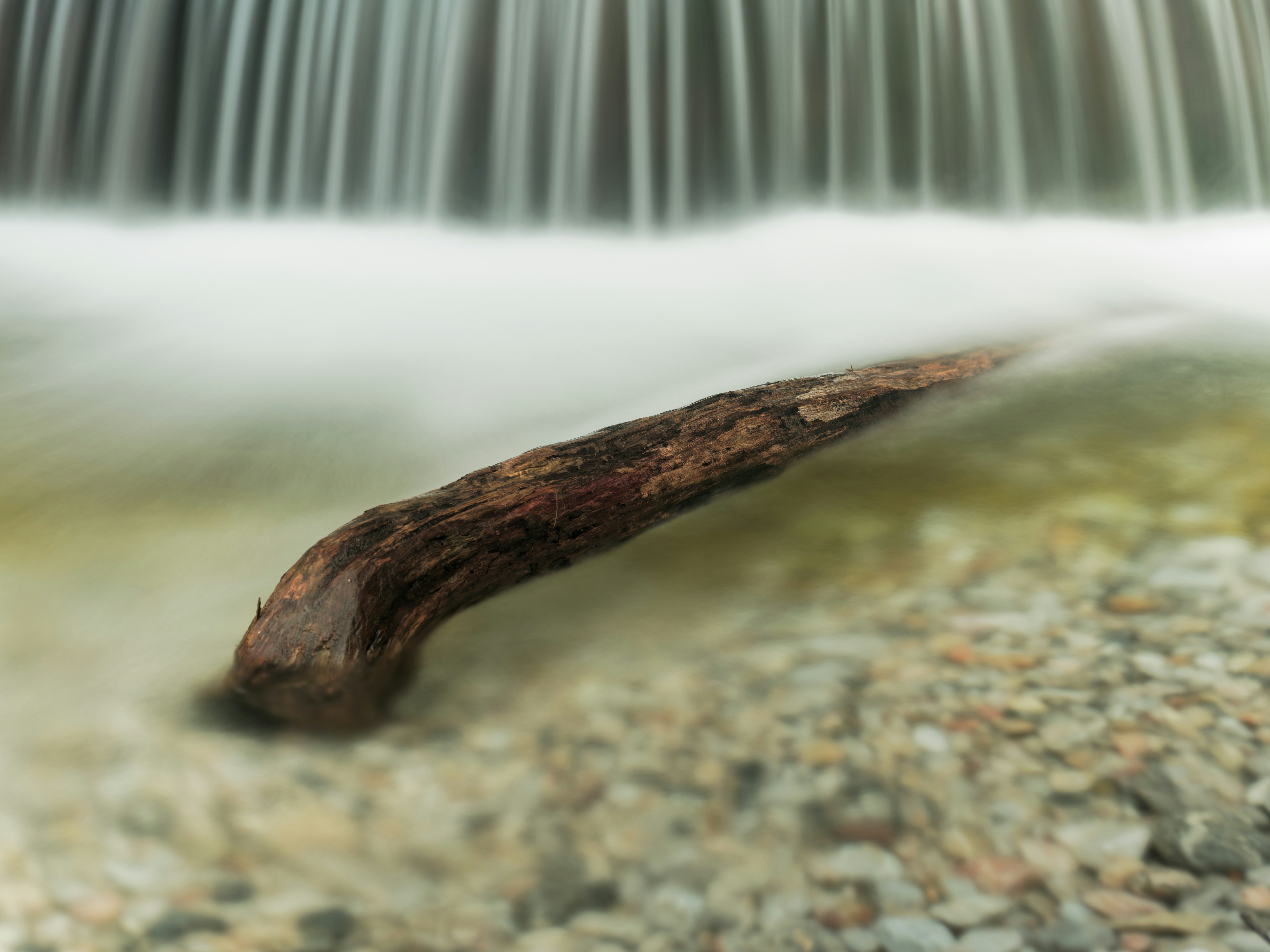 A log sticking out of the water in front of a waterfall photo – Free ...