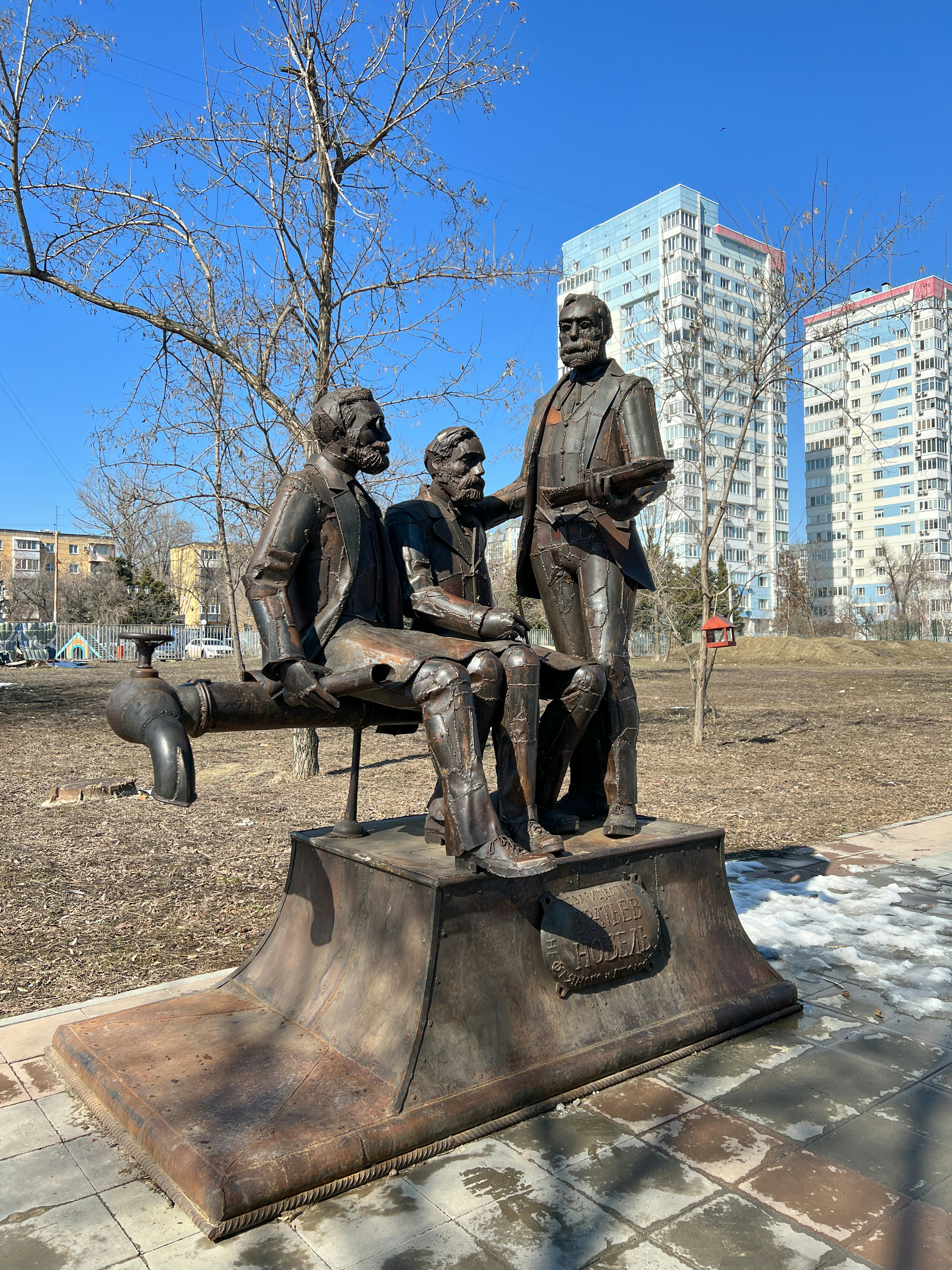 Bronze Trio in a City Park, Framed by a Modern Skyline