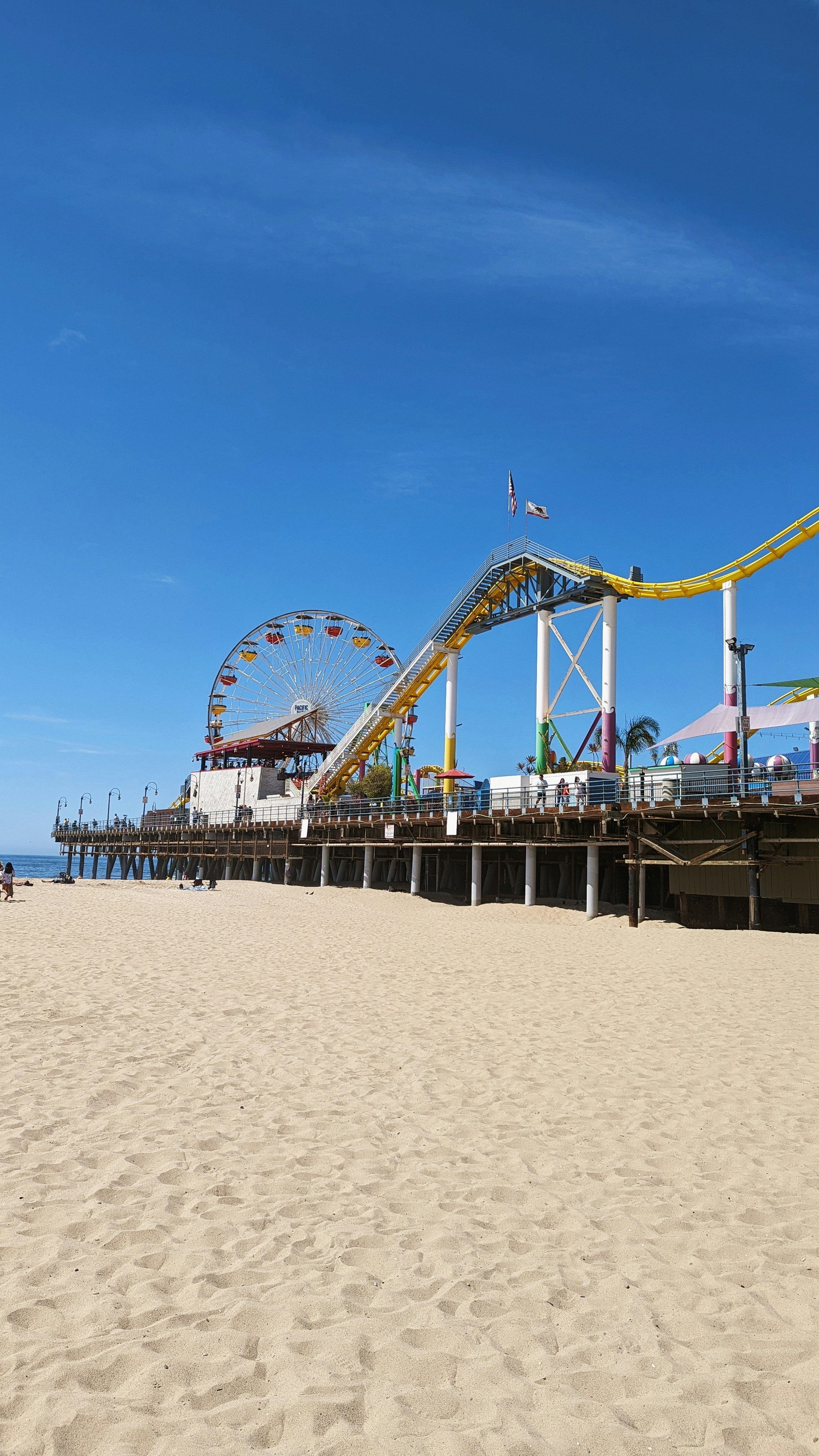 A roller coaster on a sandy beach next to the ocean photo – Free Santa ...