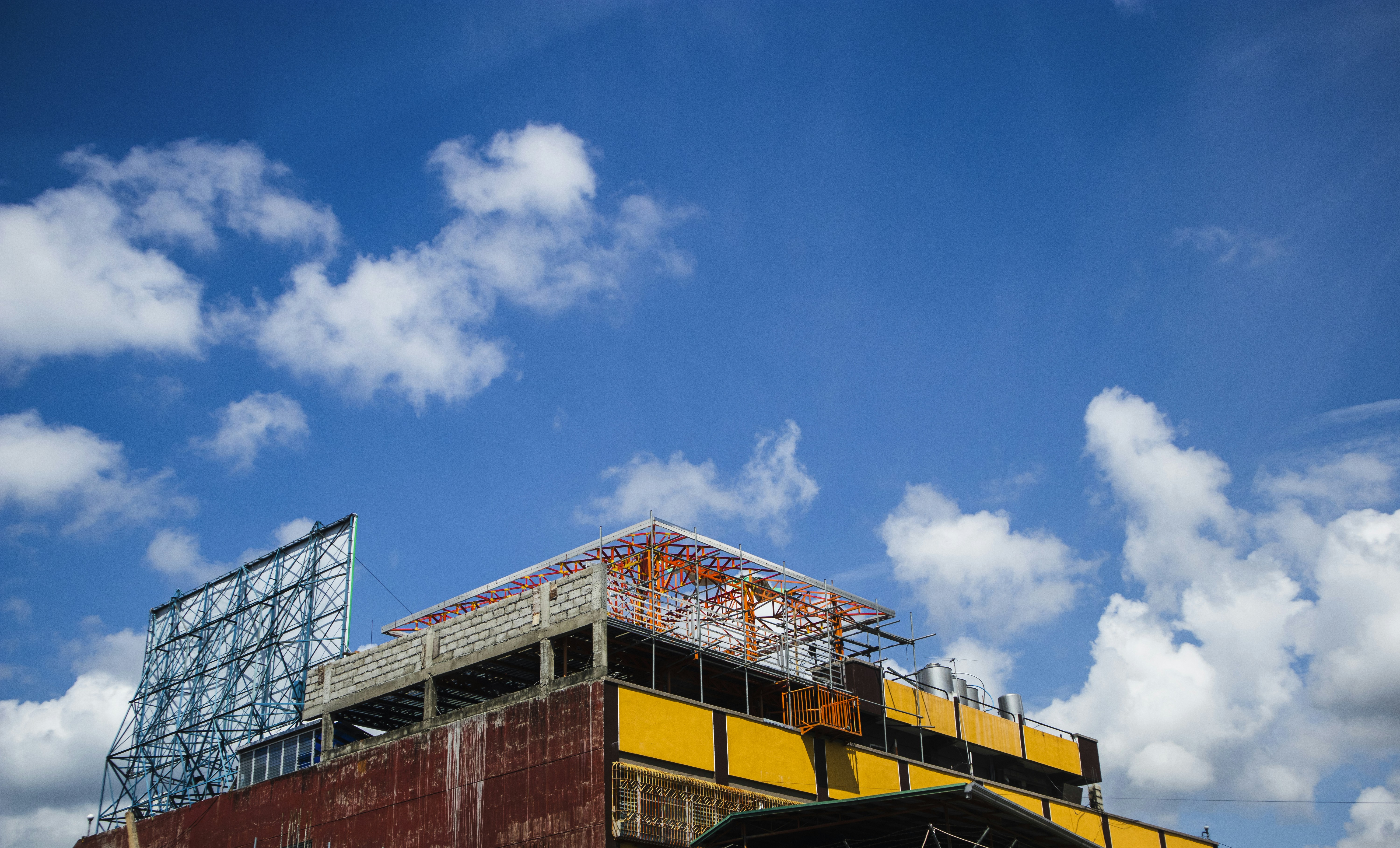 A building under construction under a cloudy blue sky photo – Free ...