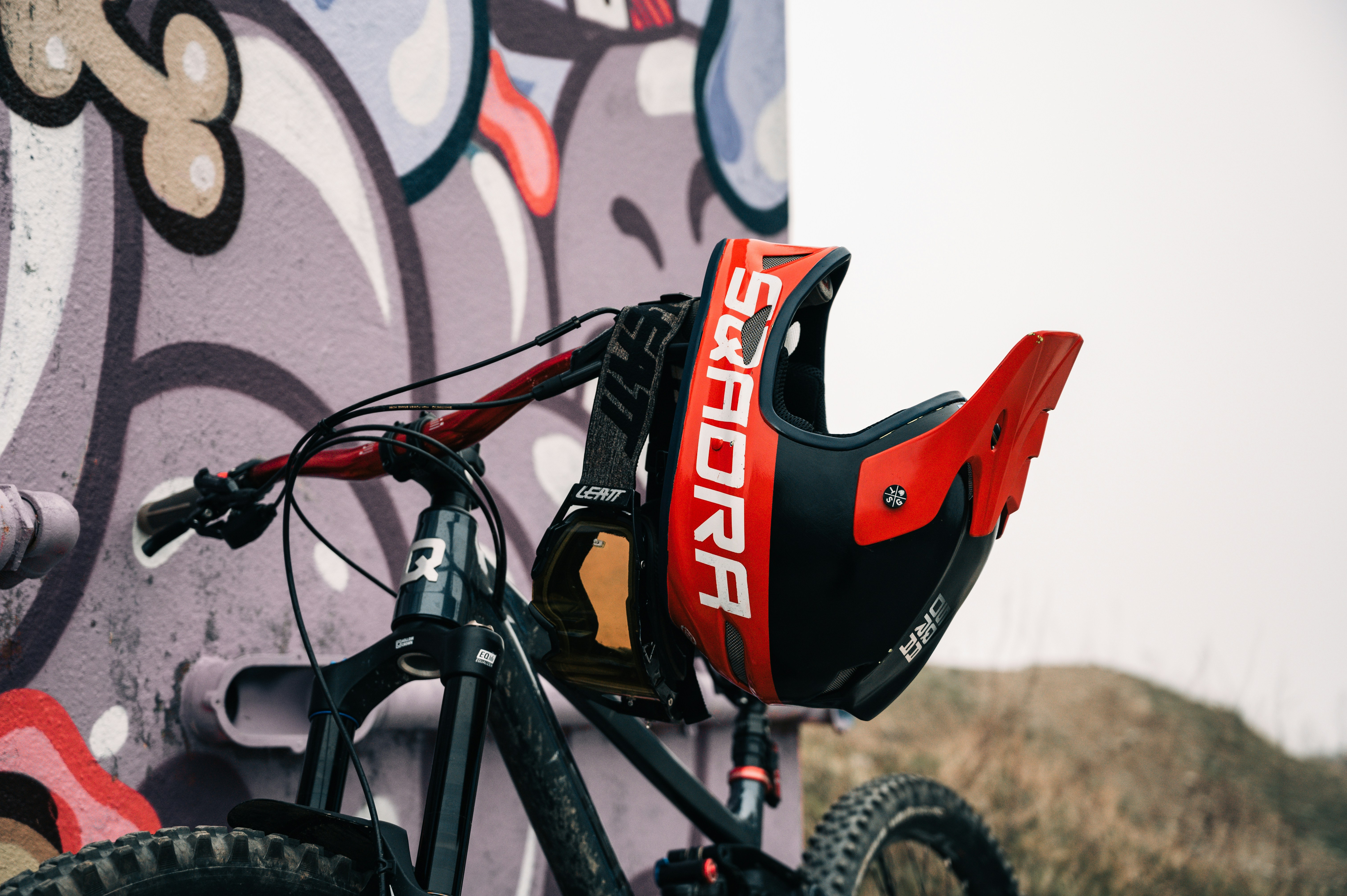 Red Helmet on a Trail-Born MTB Beside a Graffiti Wall