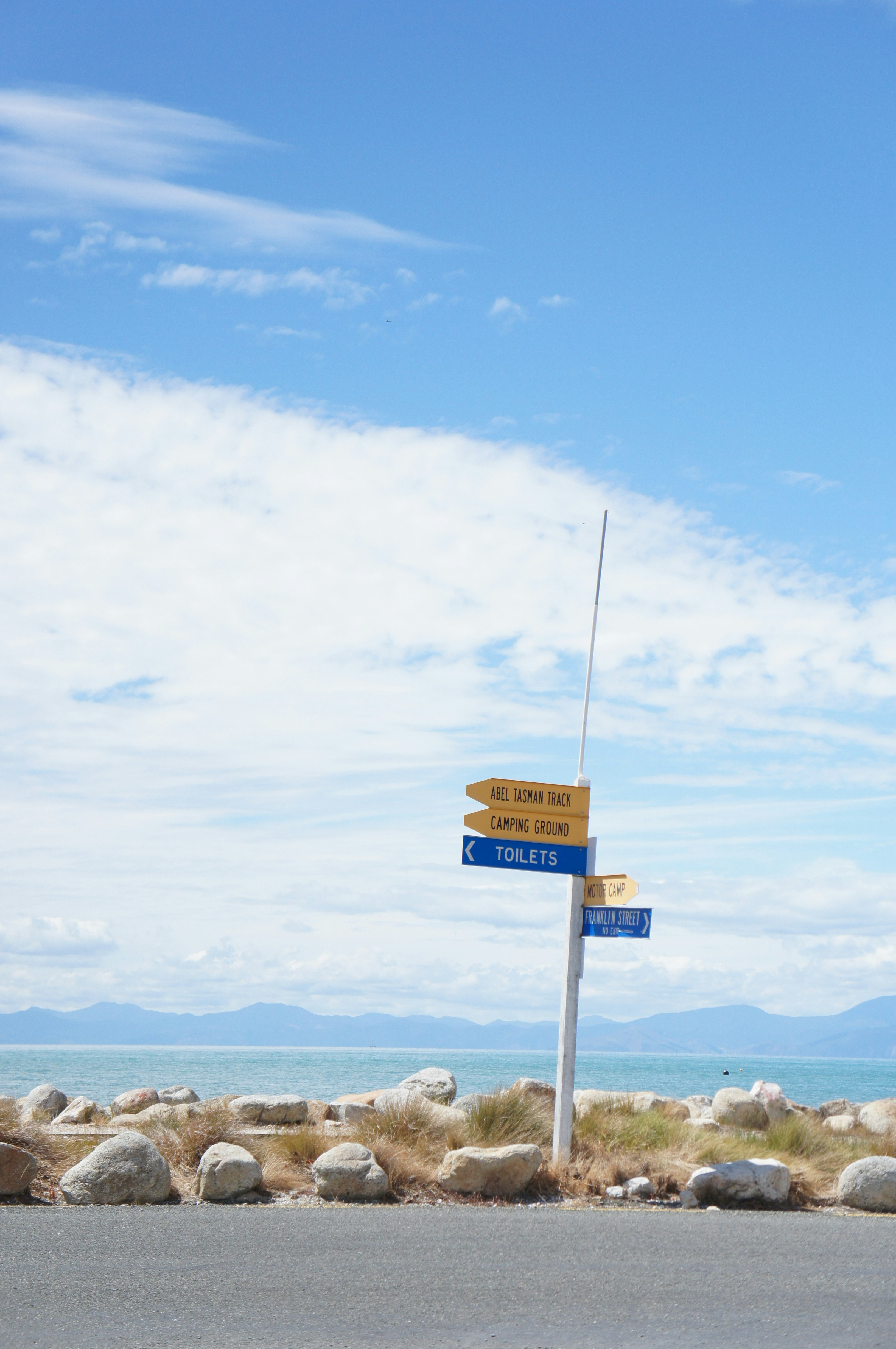 Signpost by the Seaside: A Quiet Beacon Over Rock and Water