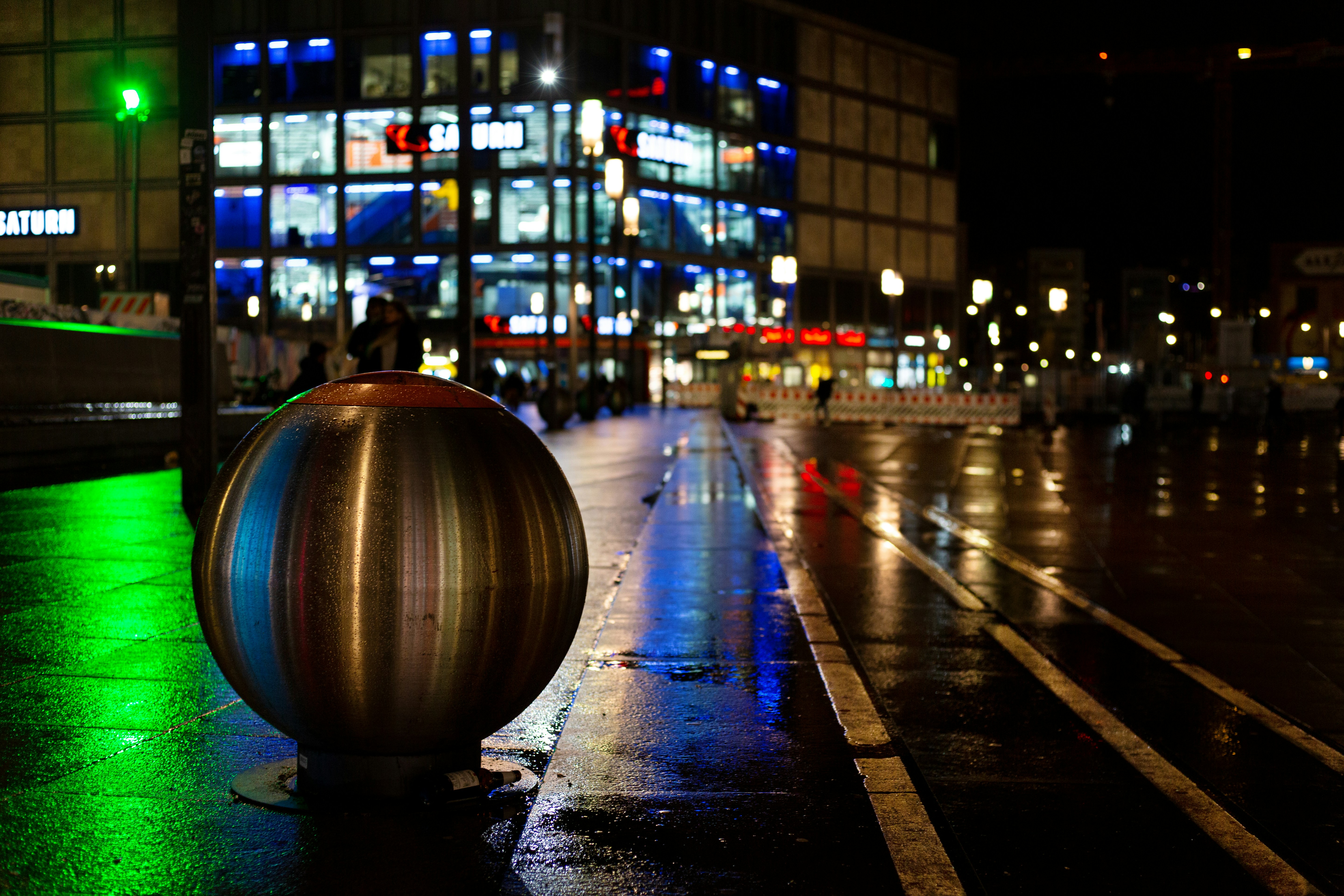 The Neon-Bathed Bollard: A Night Portrait on a Rain-Soaked Avenue