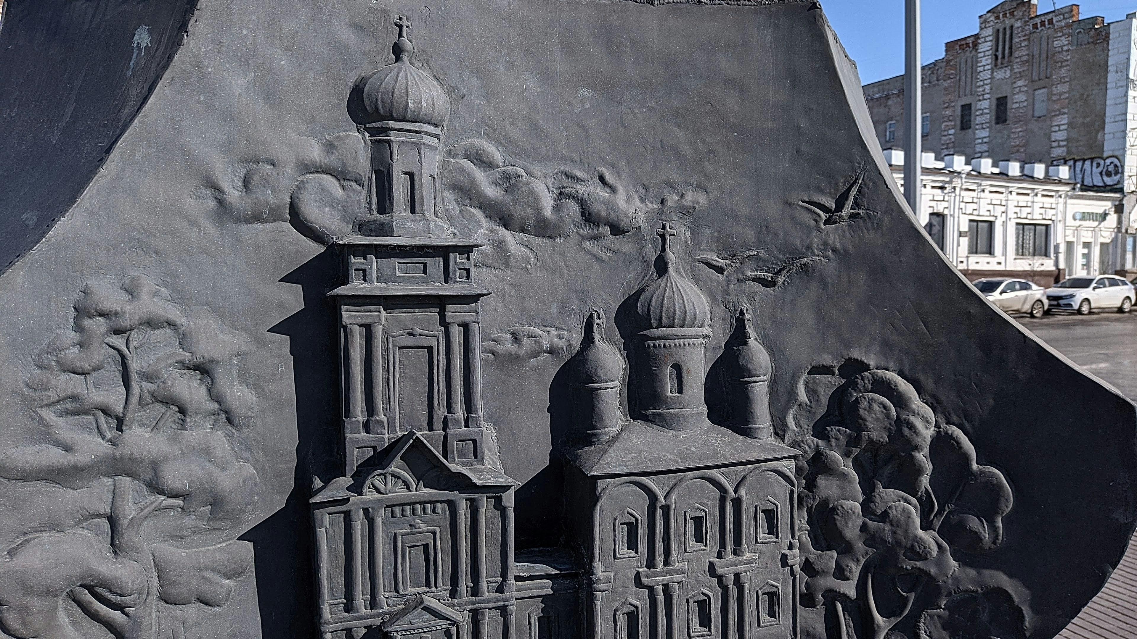 Detailed relief sculpture depicting historic architecture with domed towers under a clear sky.
