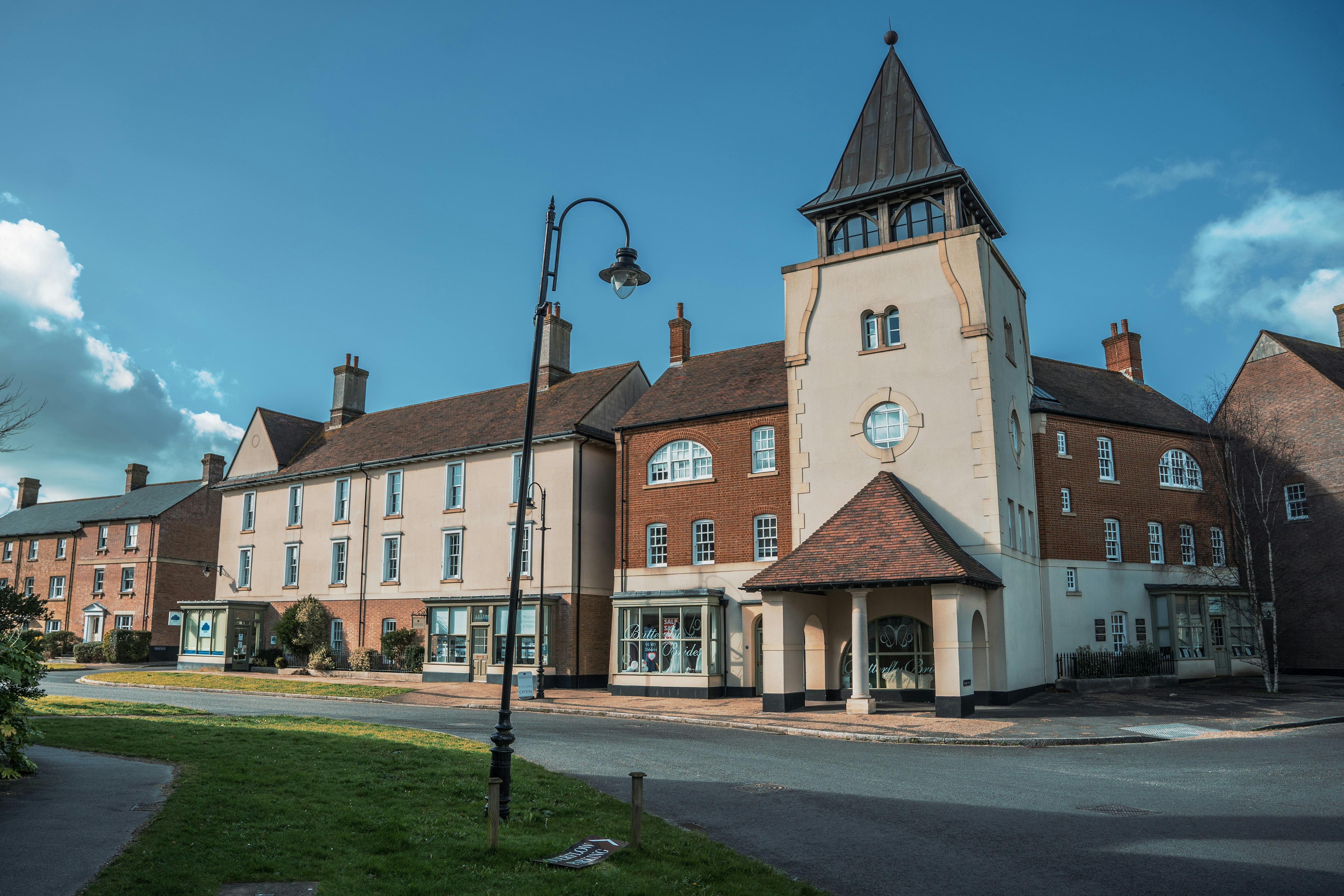Traditional English buildings with a prominent clock tower under a vibrant blue sky.