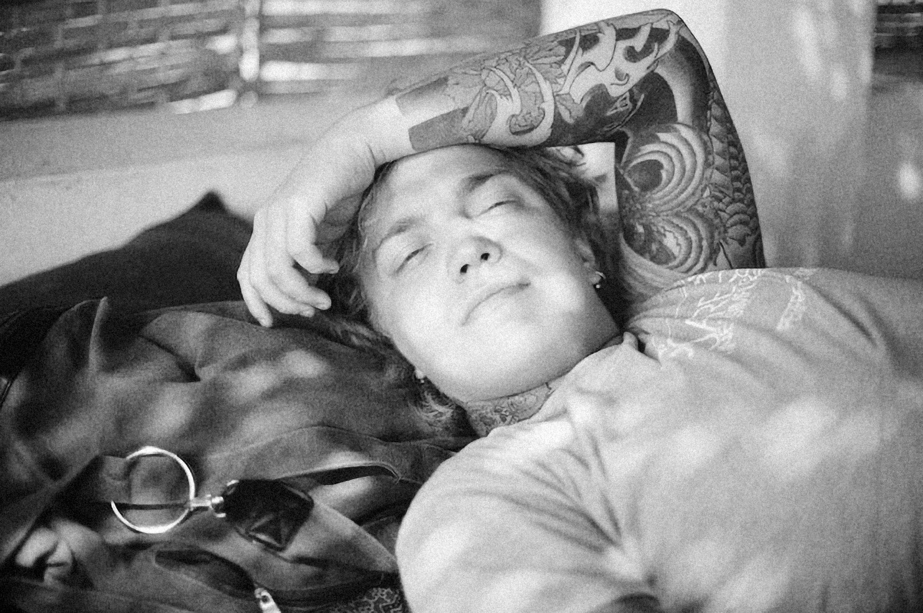 a man laying on a bed with a tattoo on his arm