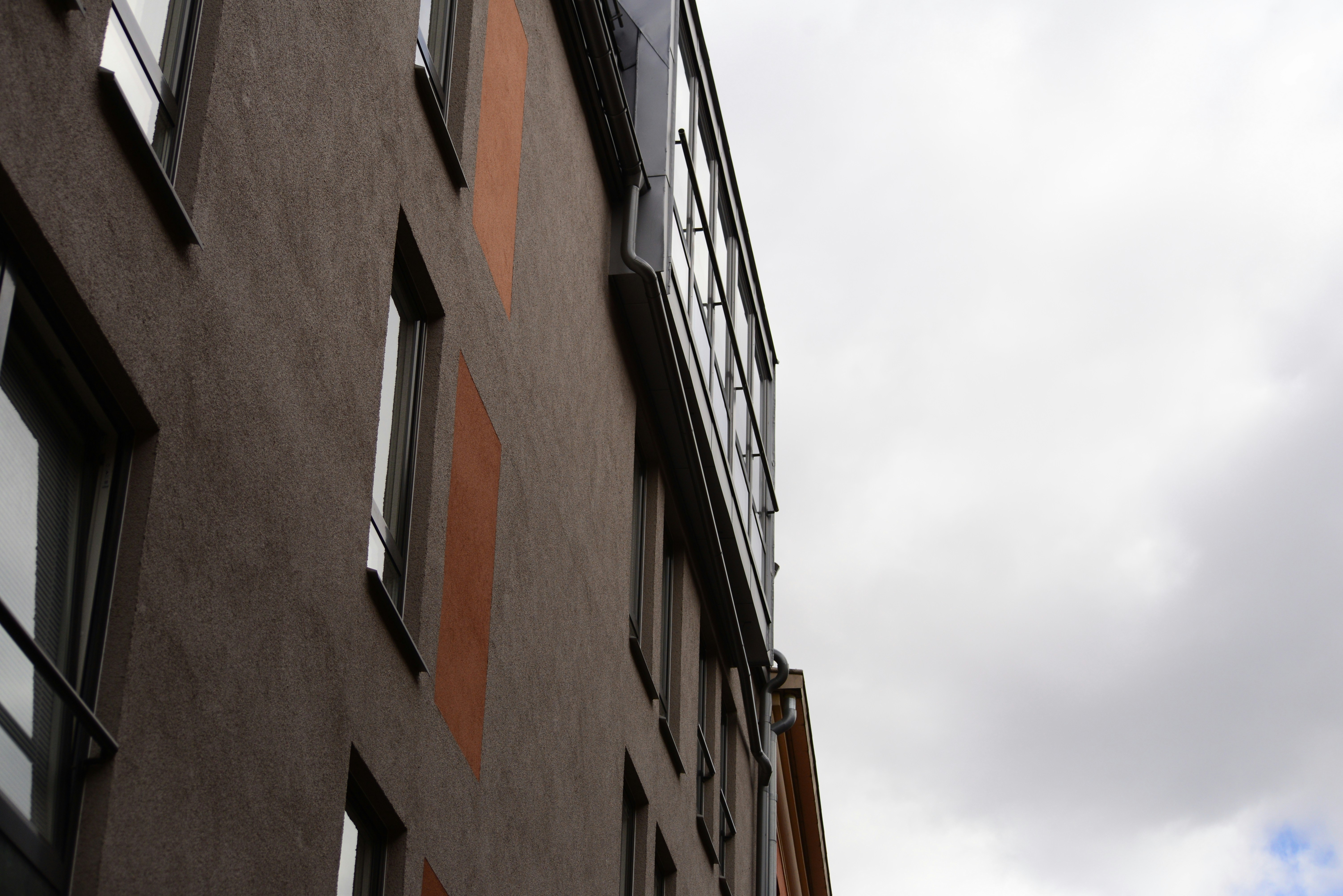 Angular view of a contemporary building showcasing a mix of textures and materials against a cloudy sky.