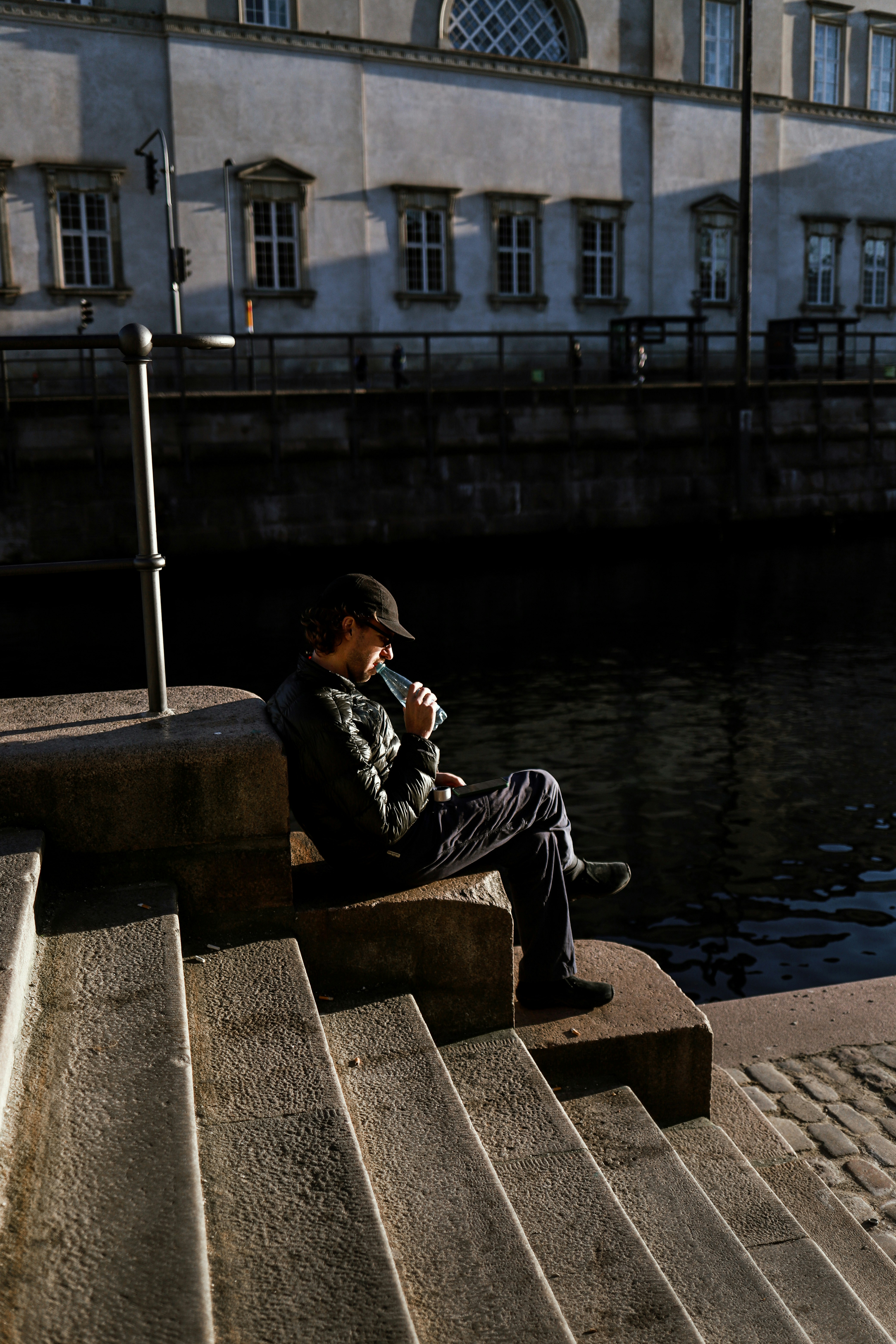 Un homme assis sur un rebord à côté d’un plan d’eau photo – Photo ...