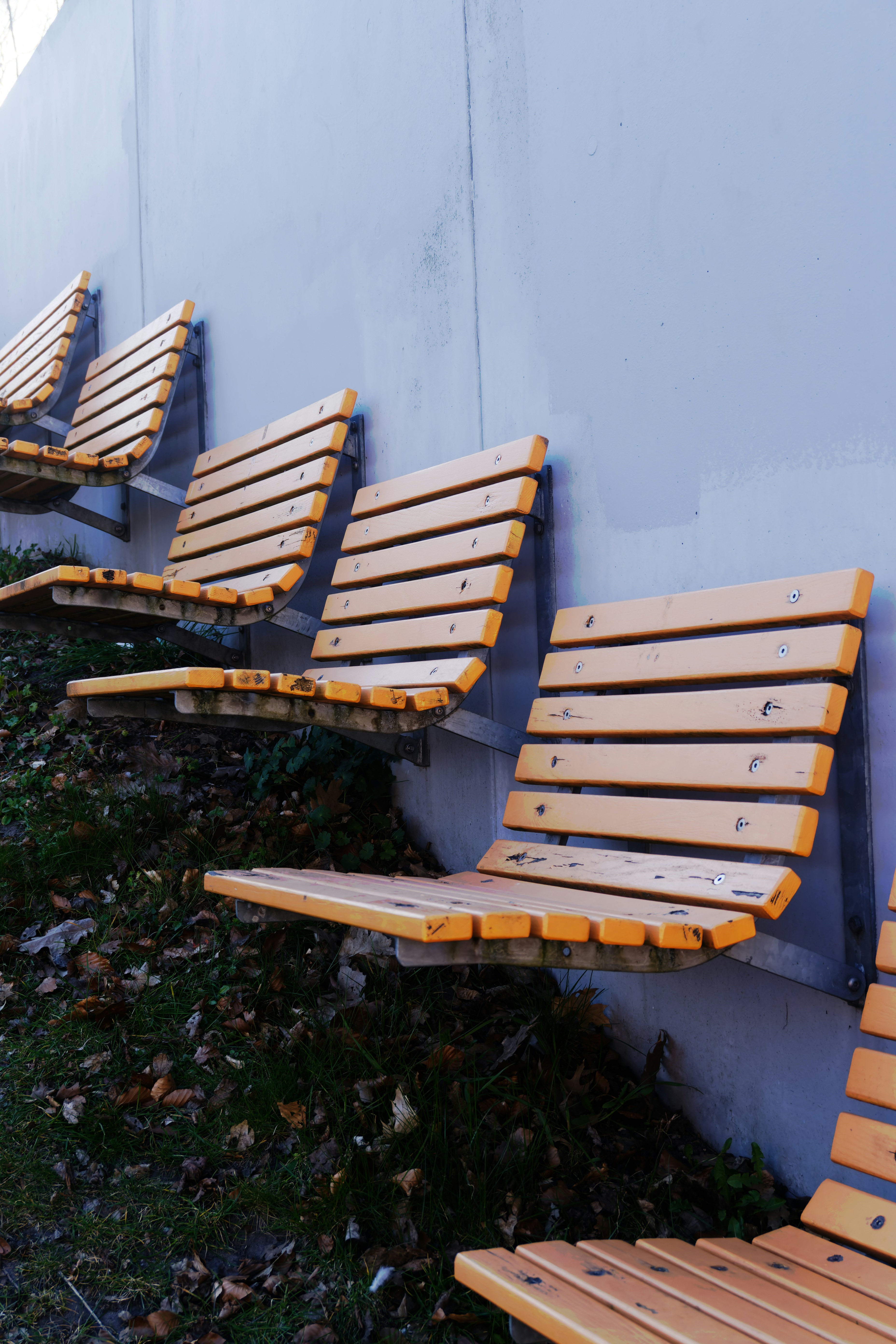 a row of wooden benches sitting next to a wall