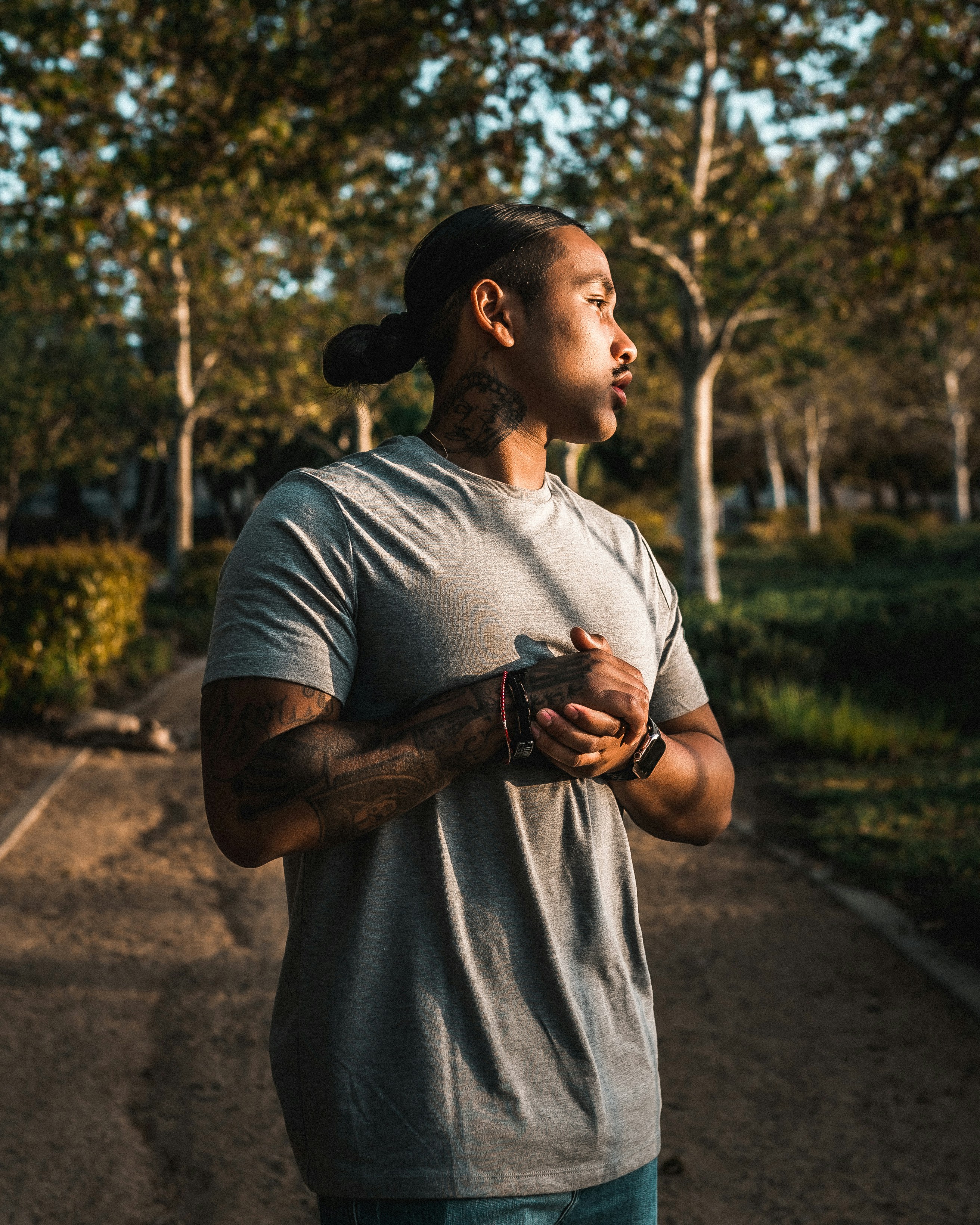 Un homme avec une queue de cheval debout dans un parc photo – Photo La ...