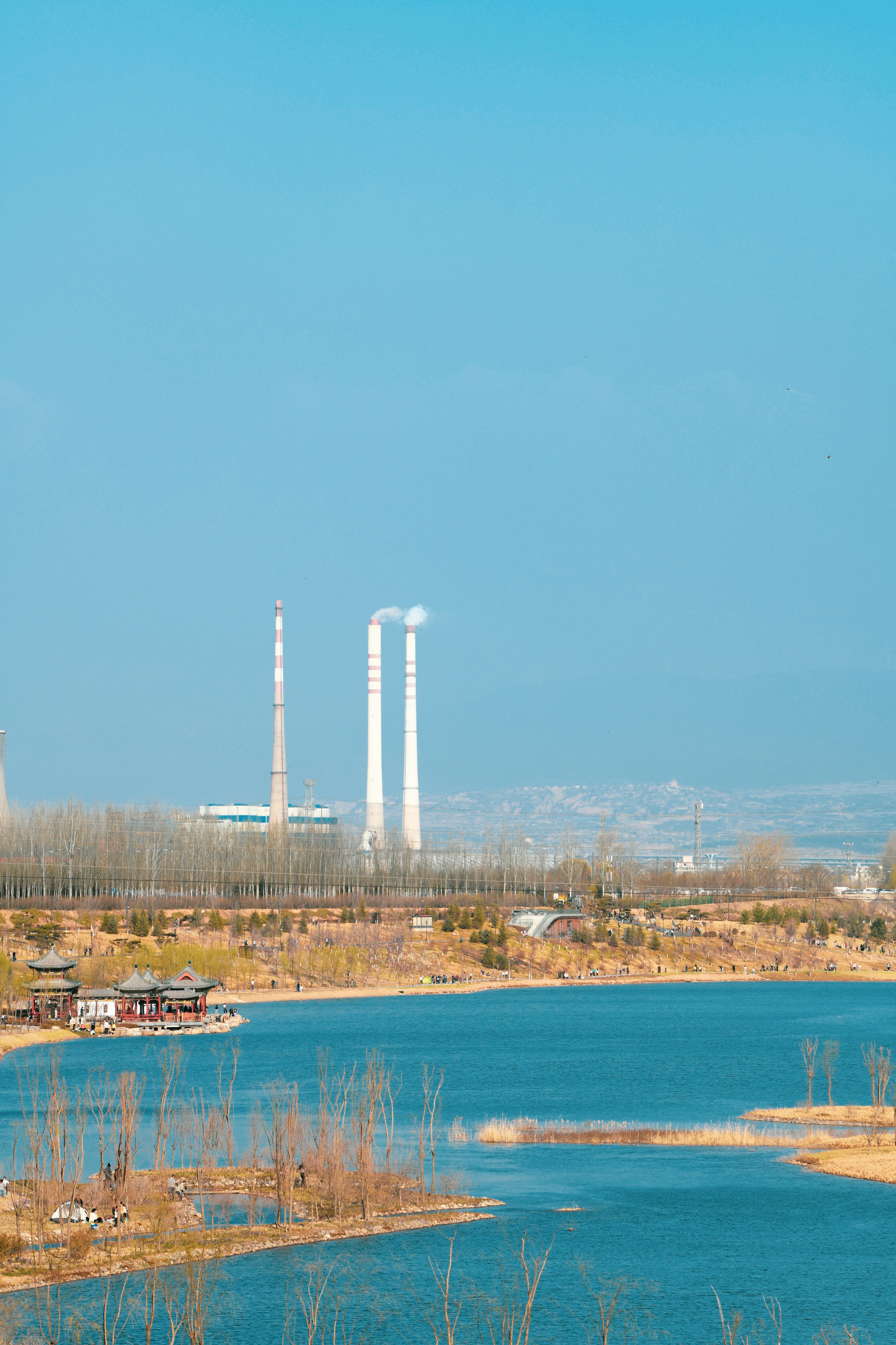 a large body of water with a factory in the background
