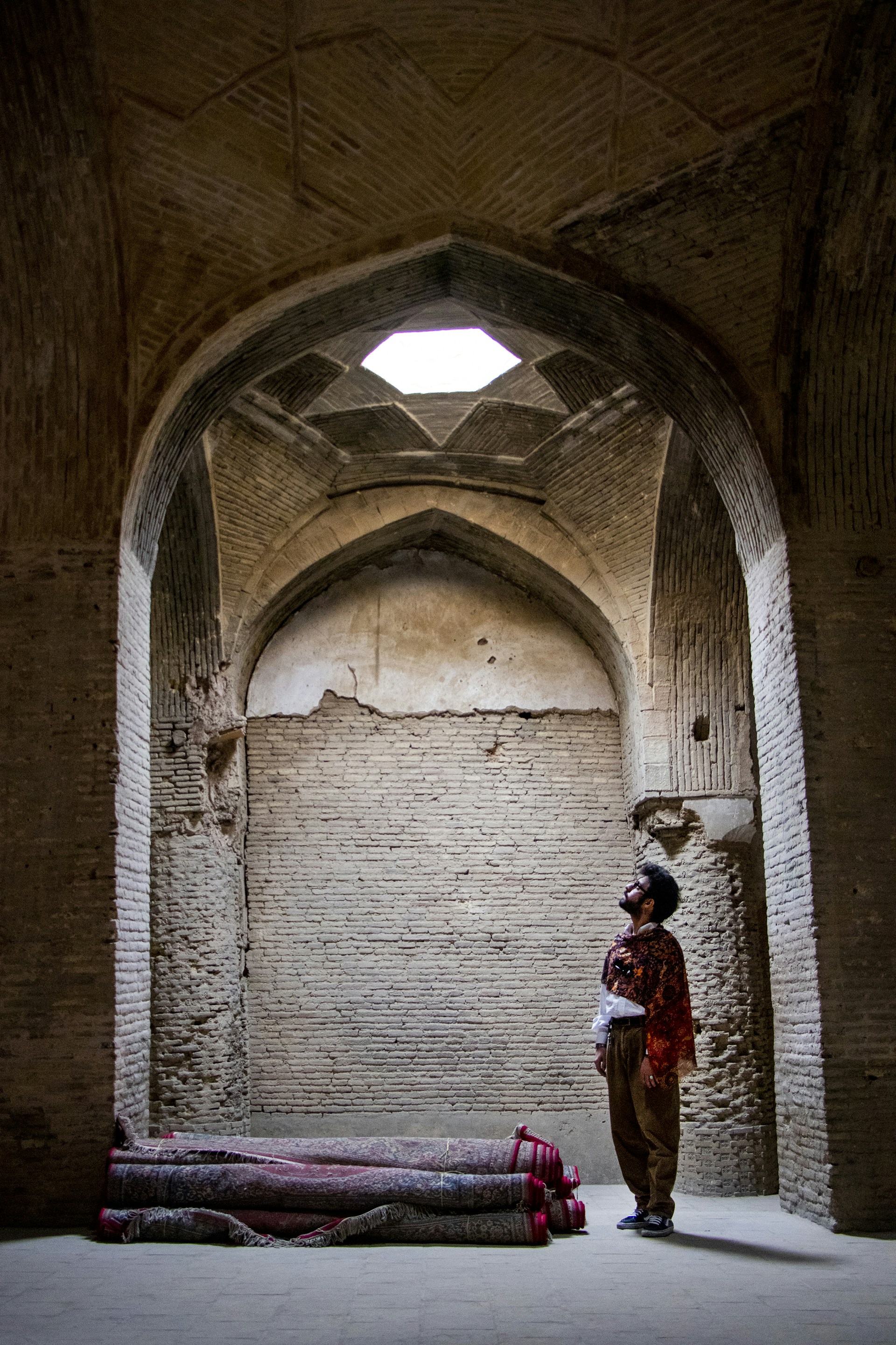 Foto zum Thema Ein Mann steht in einem Torbogen mit einem Stapel Decken ...