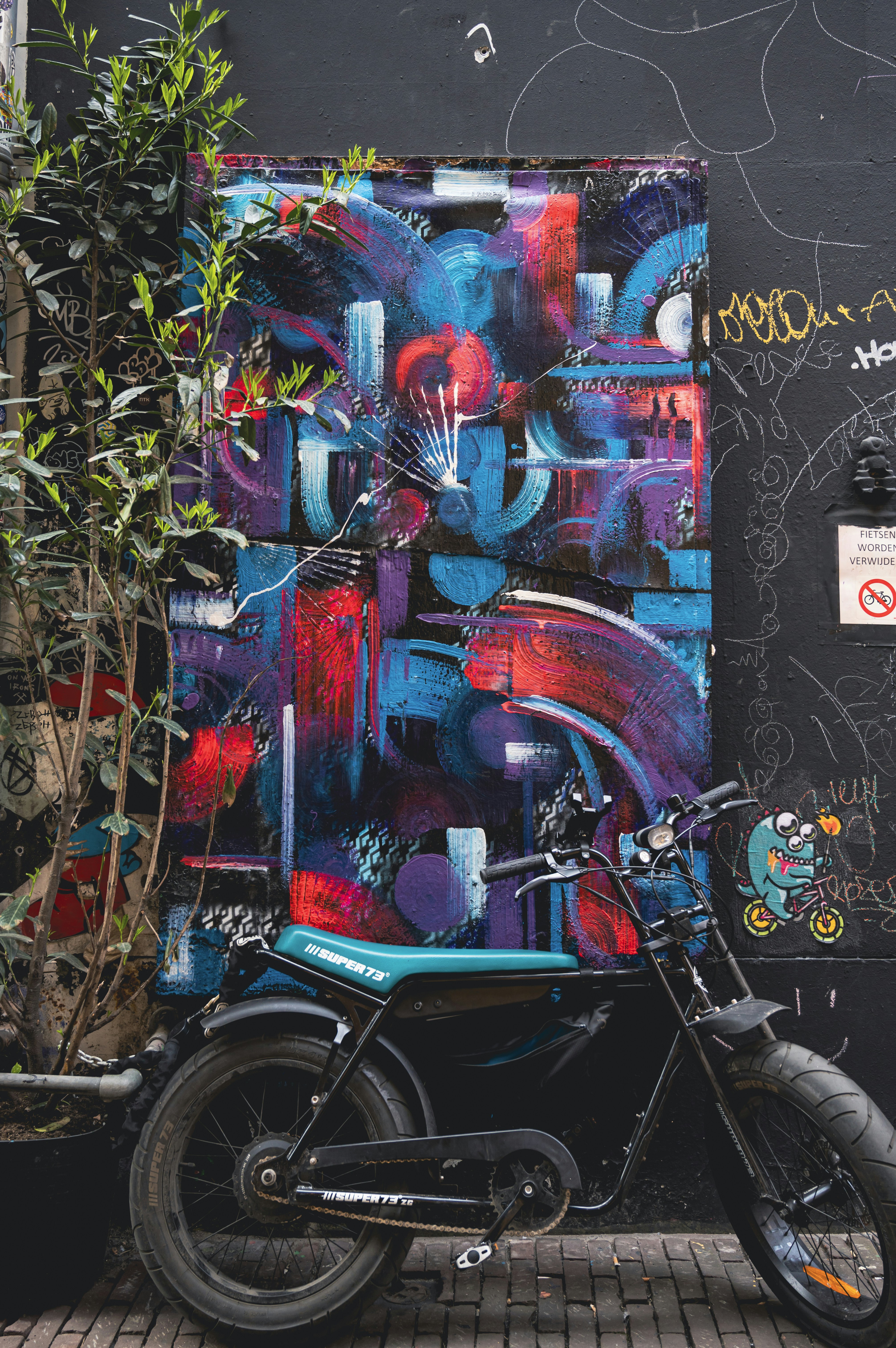 Chromatic Pulse: A mural of color with a teal motorcycle resting at its base