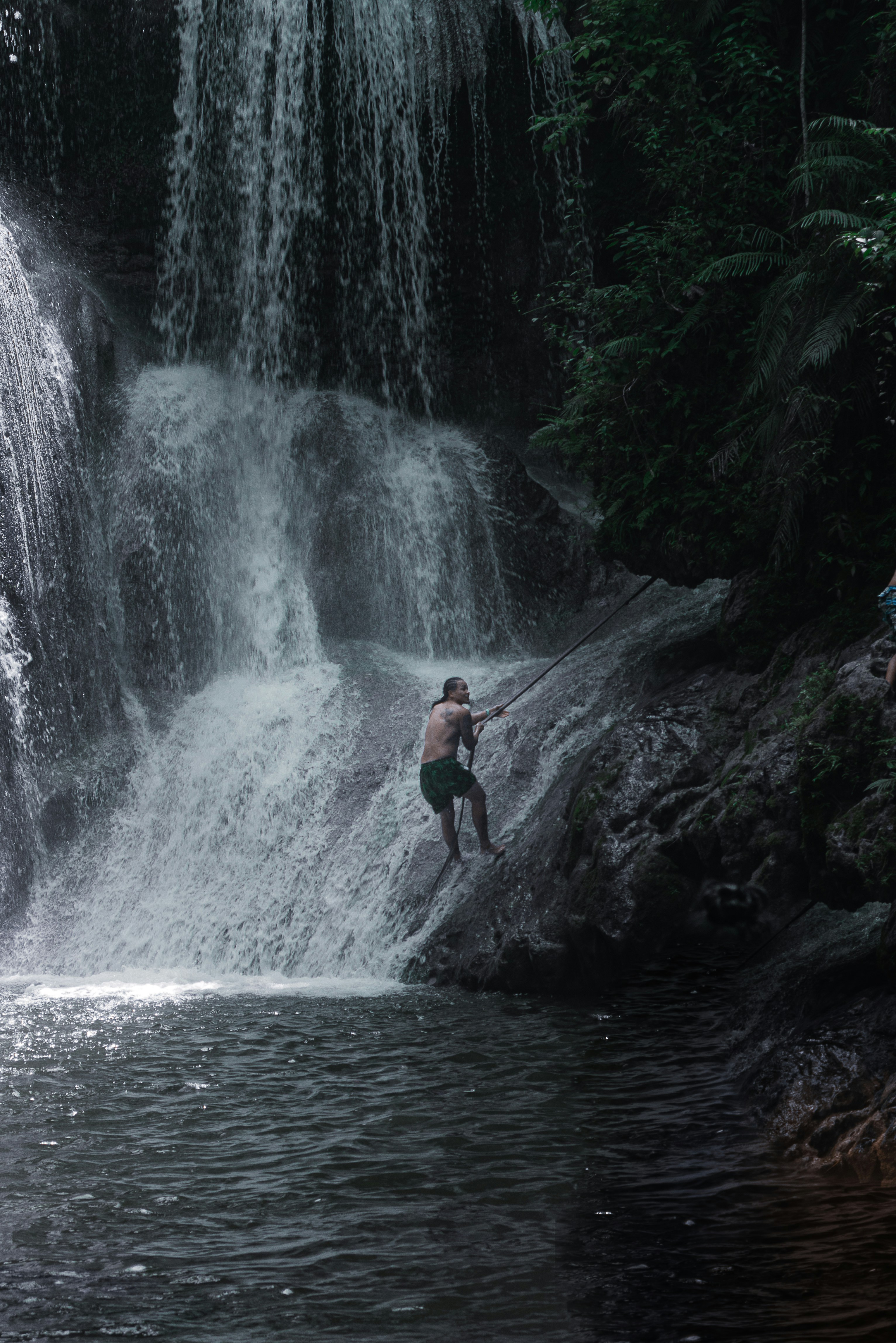 a man standing on a rock in front of a waterfall