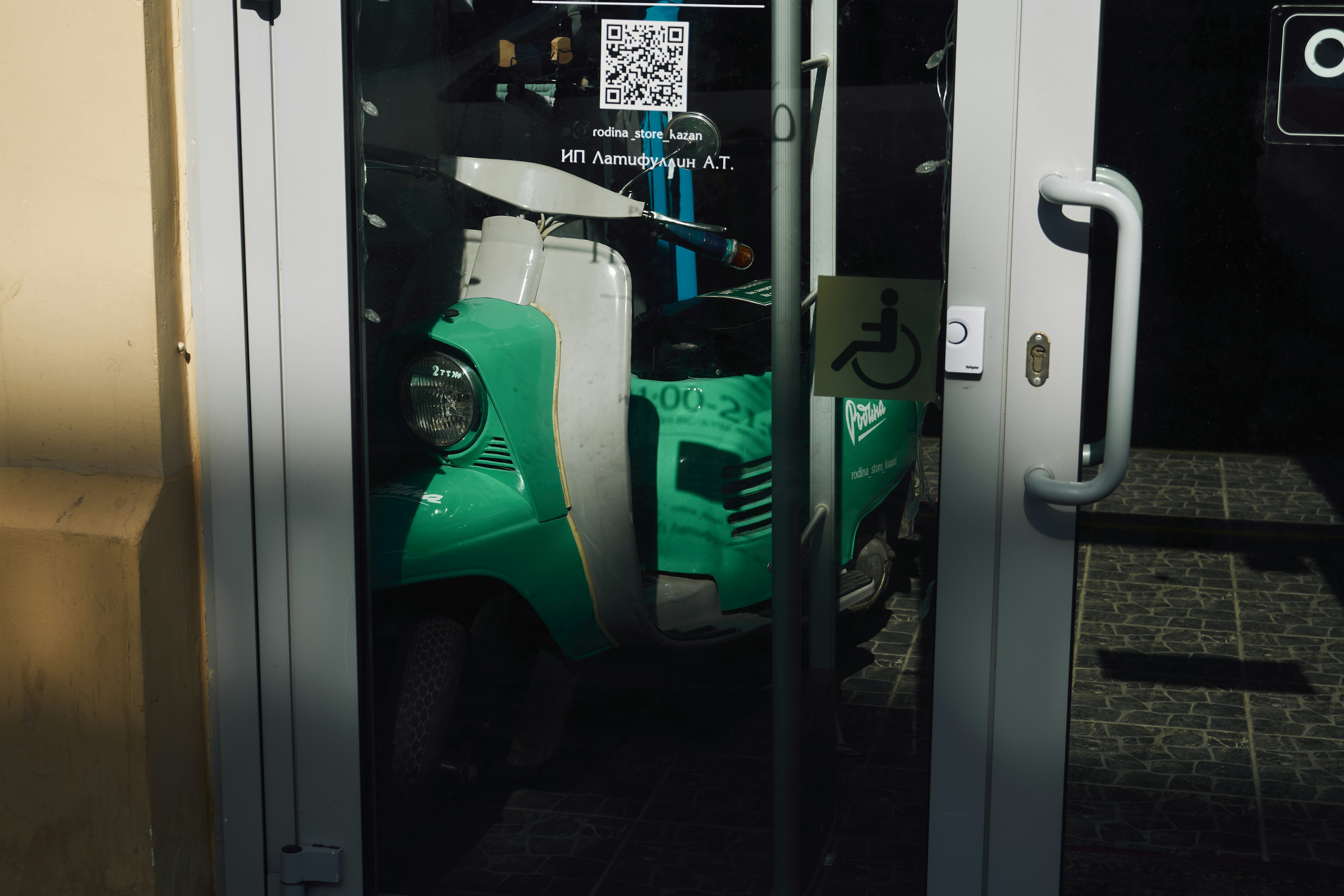 Scooter beneath the glass: a dimly lit storefront doorway reflection