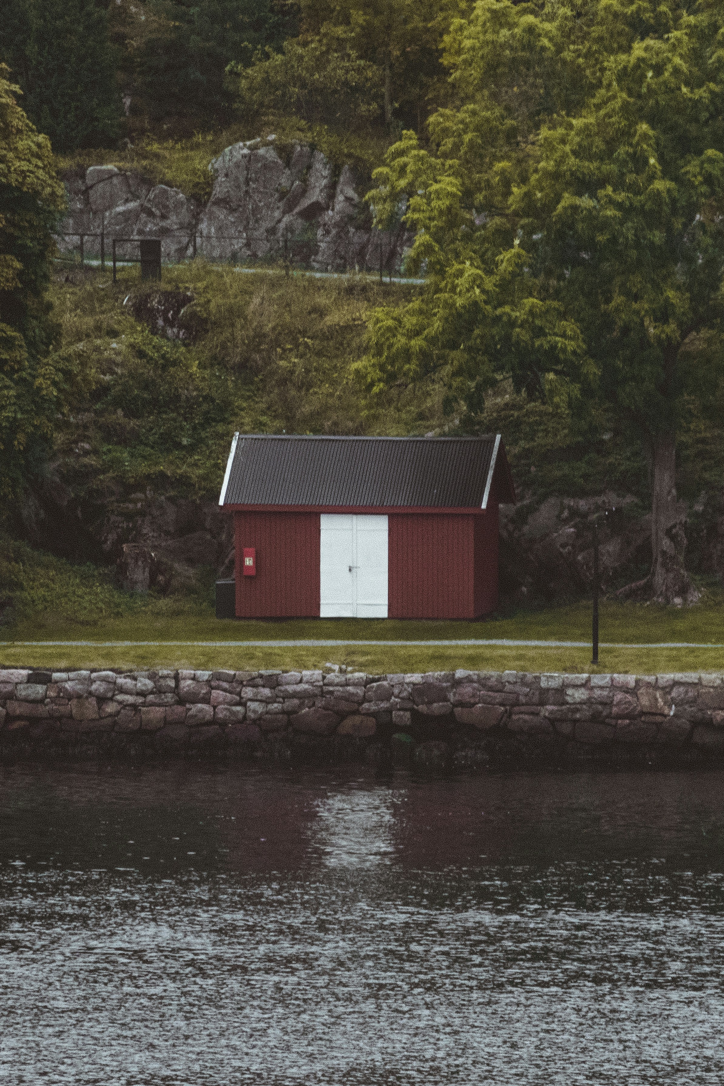 A small red building sitting next to a body of water photo – Free Grey ...