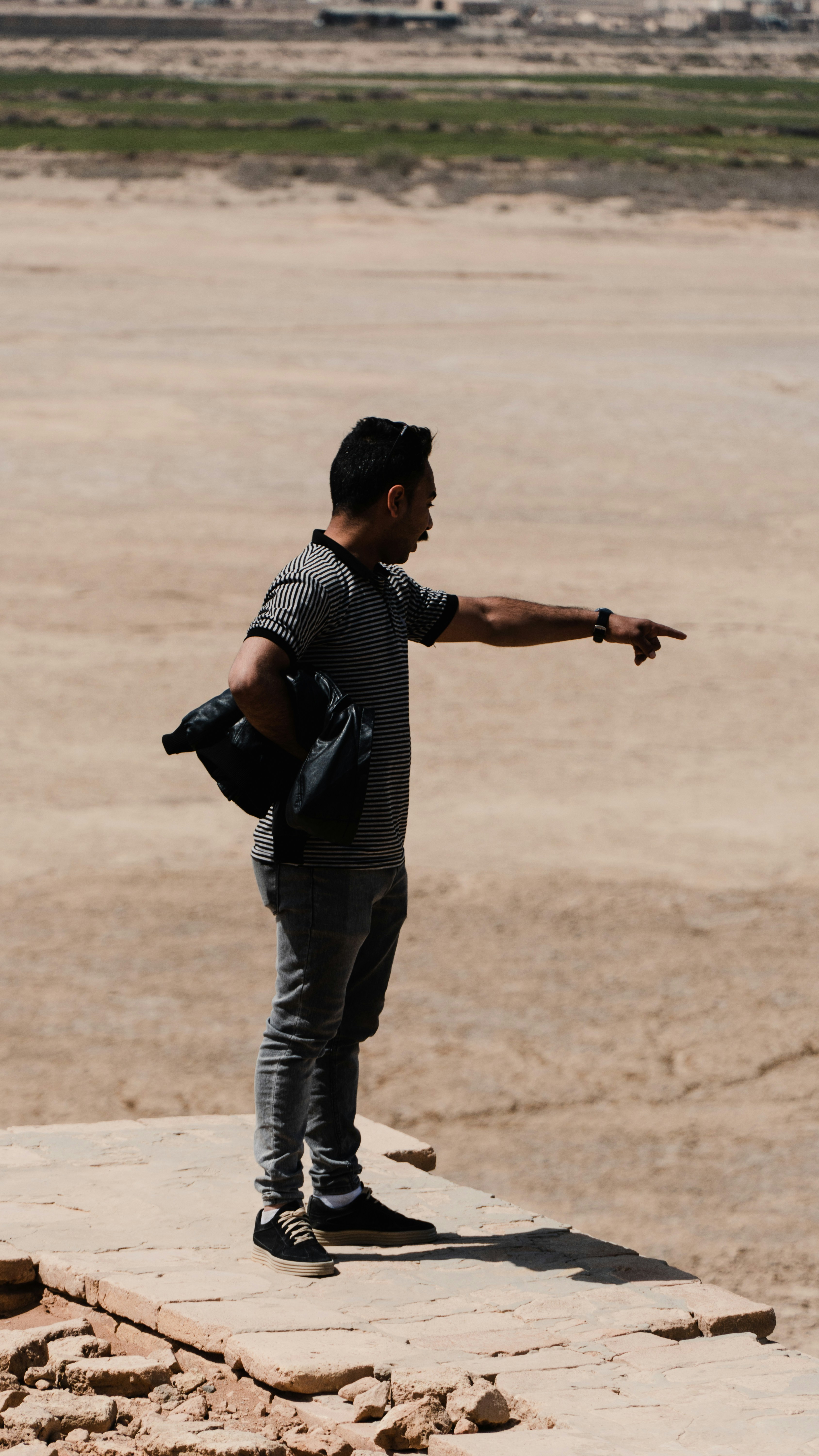 A man standing on a rock pointing at something photo – Free Brown Image ...