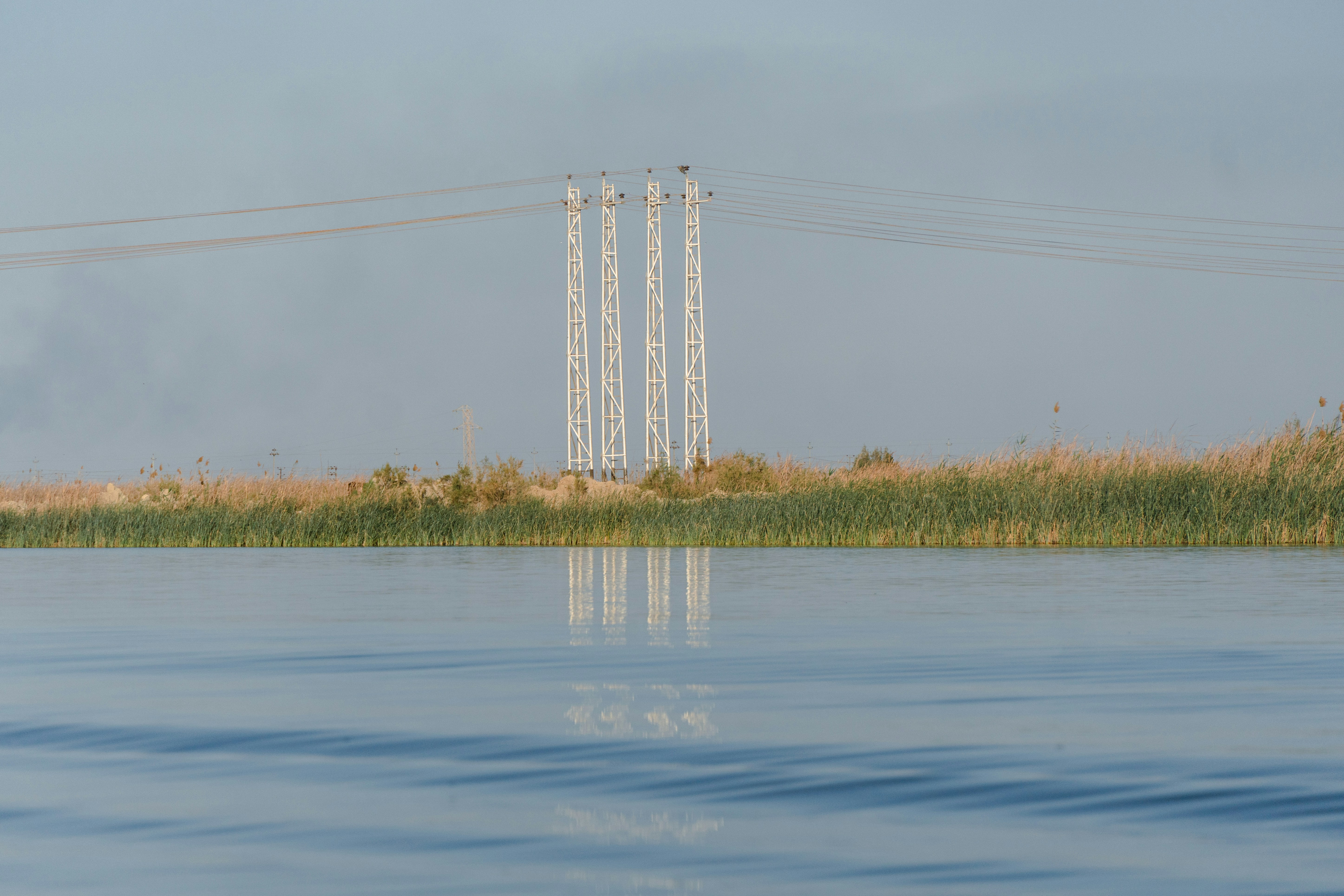A body of water with power lines in the background photo – Free Grey ...