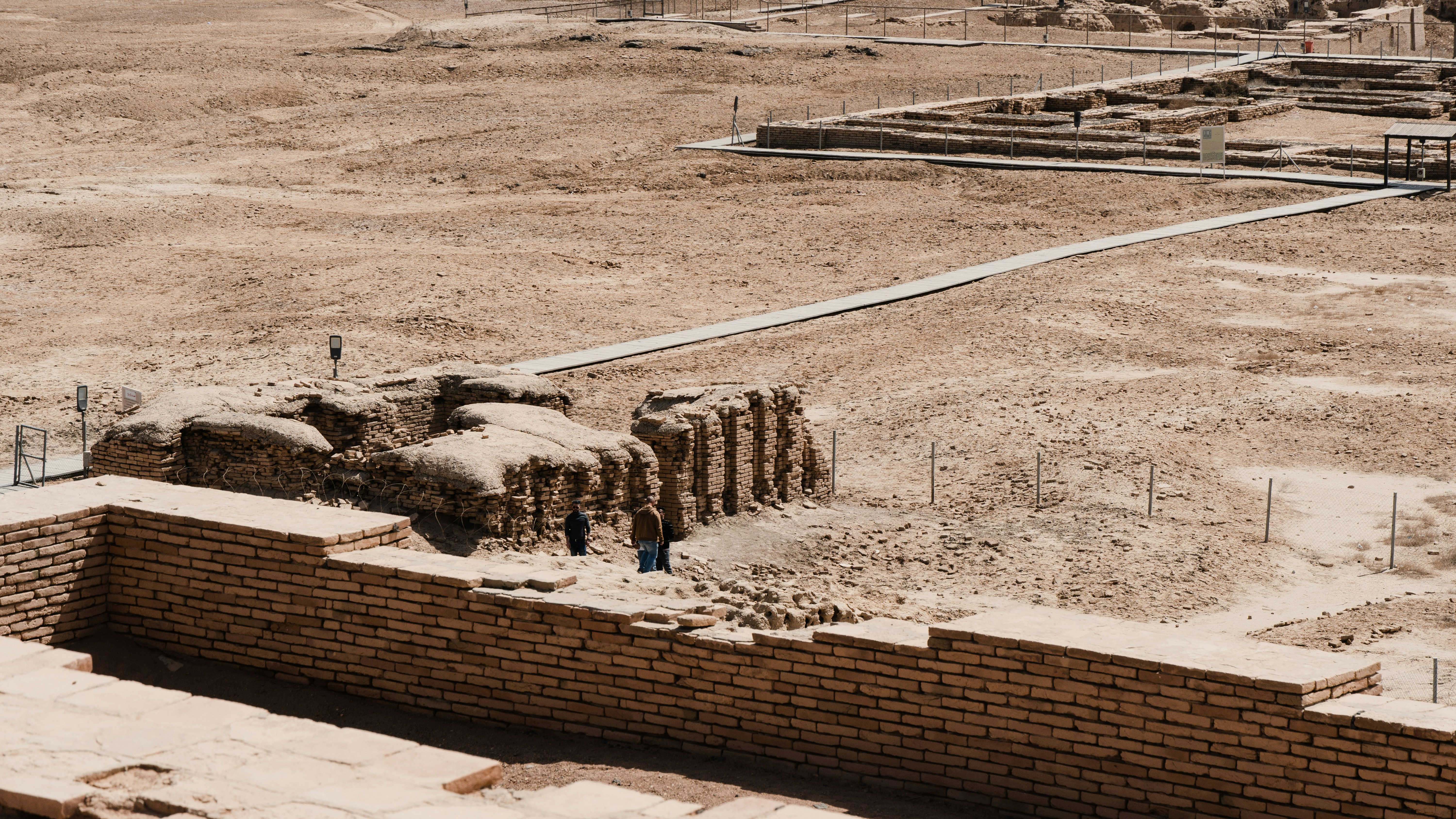 a man standing in front of a brick structure in the middle of a desert