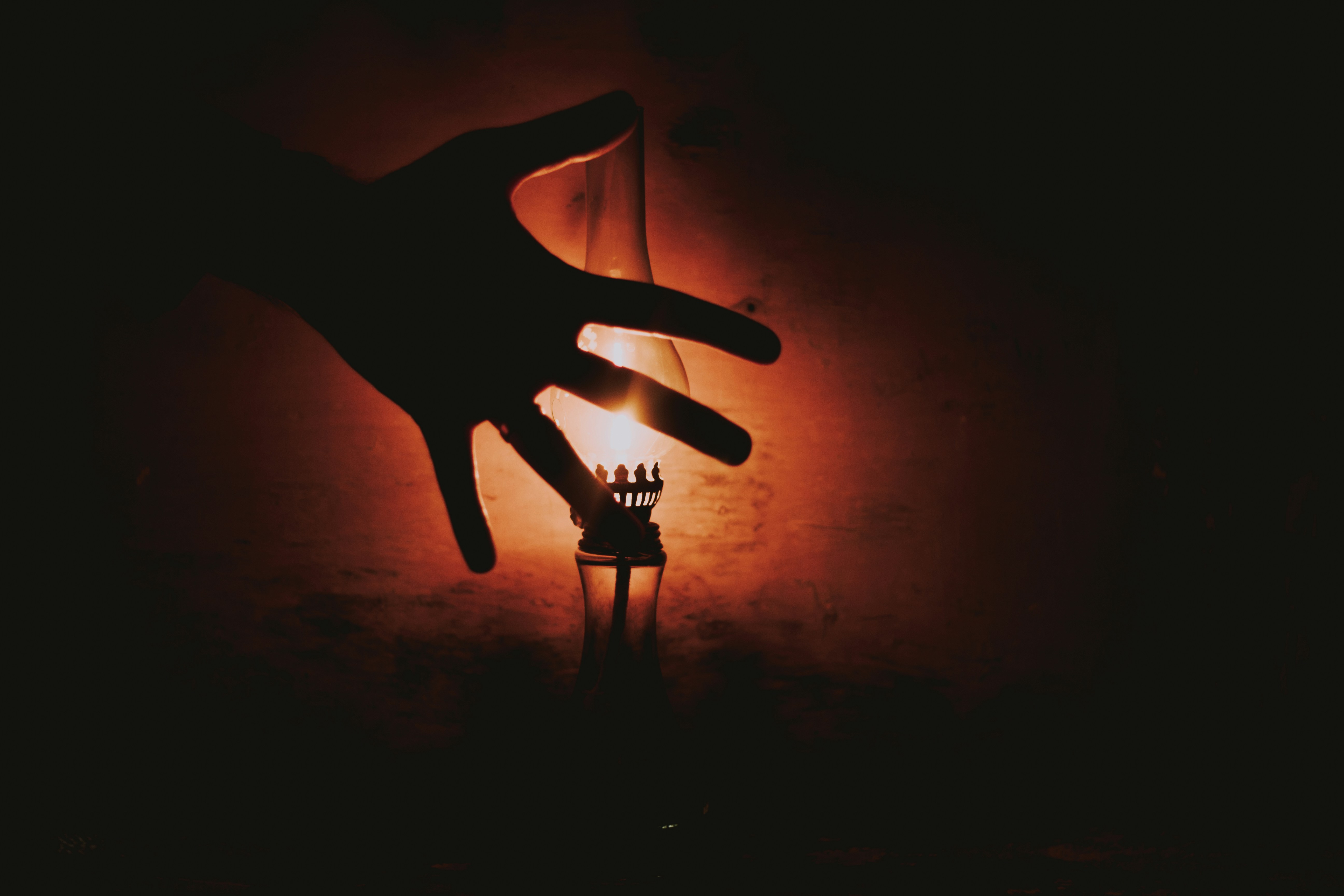 a person's hand holding a lit candle in the dark
