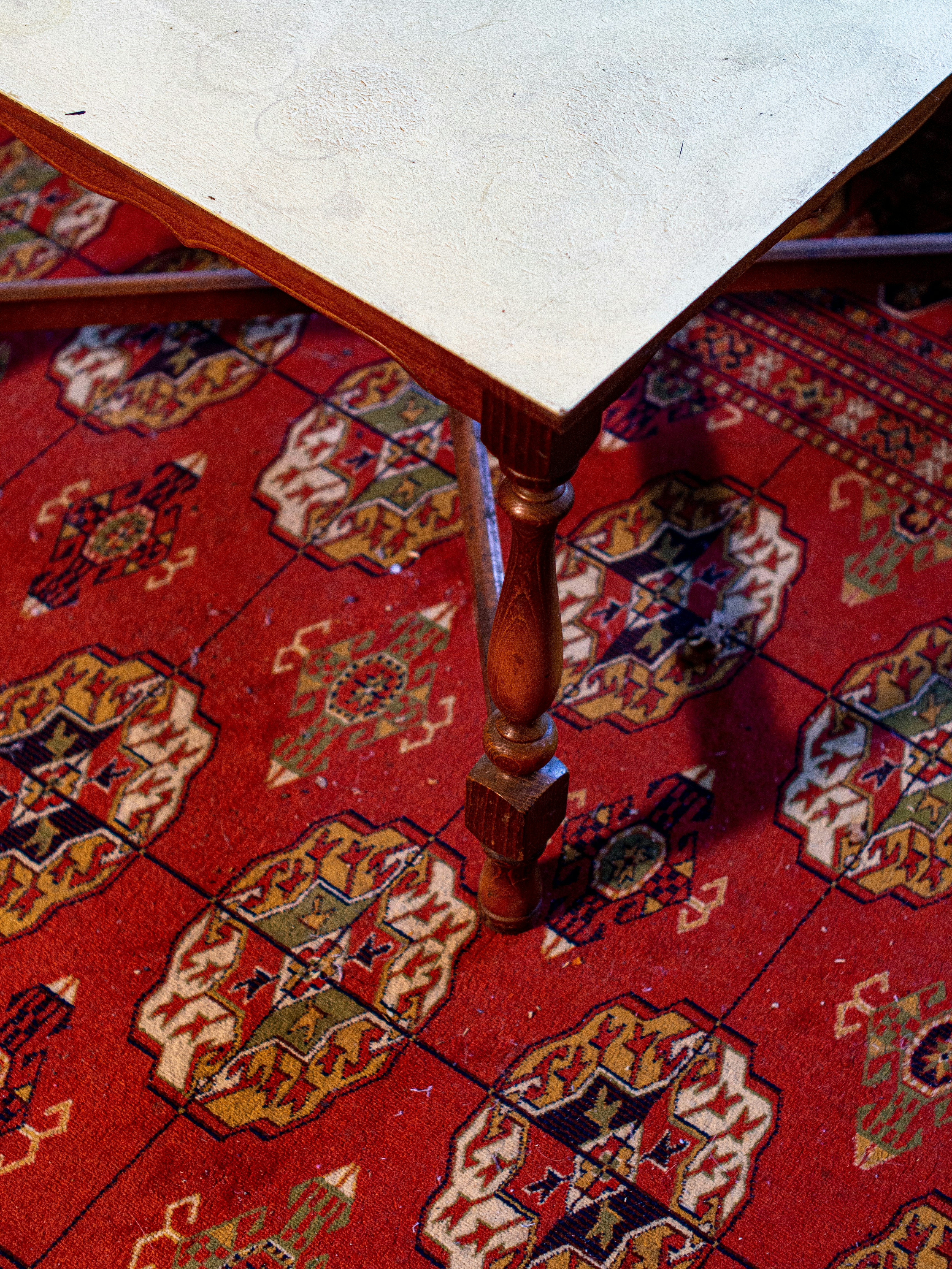 Wooden table leg resting on intricate patterned carpet, showcasing rich colors and traditional design elements.