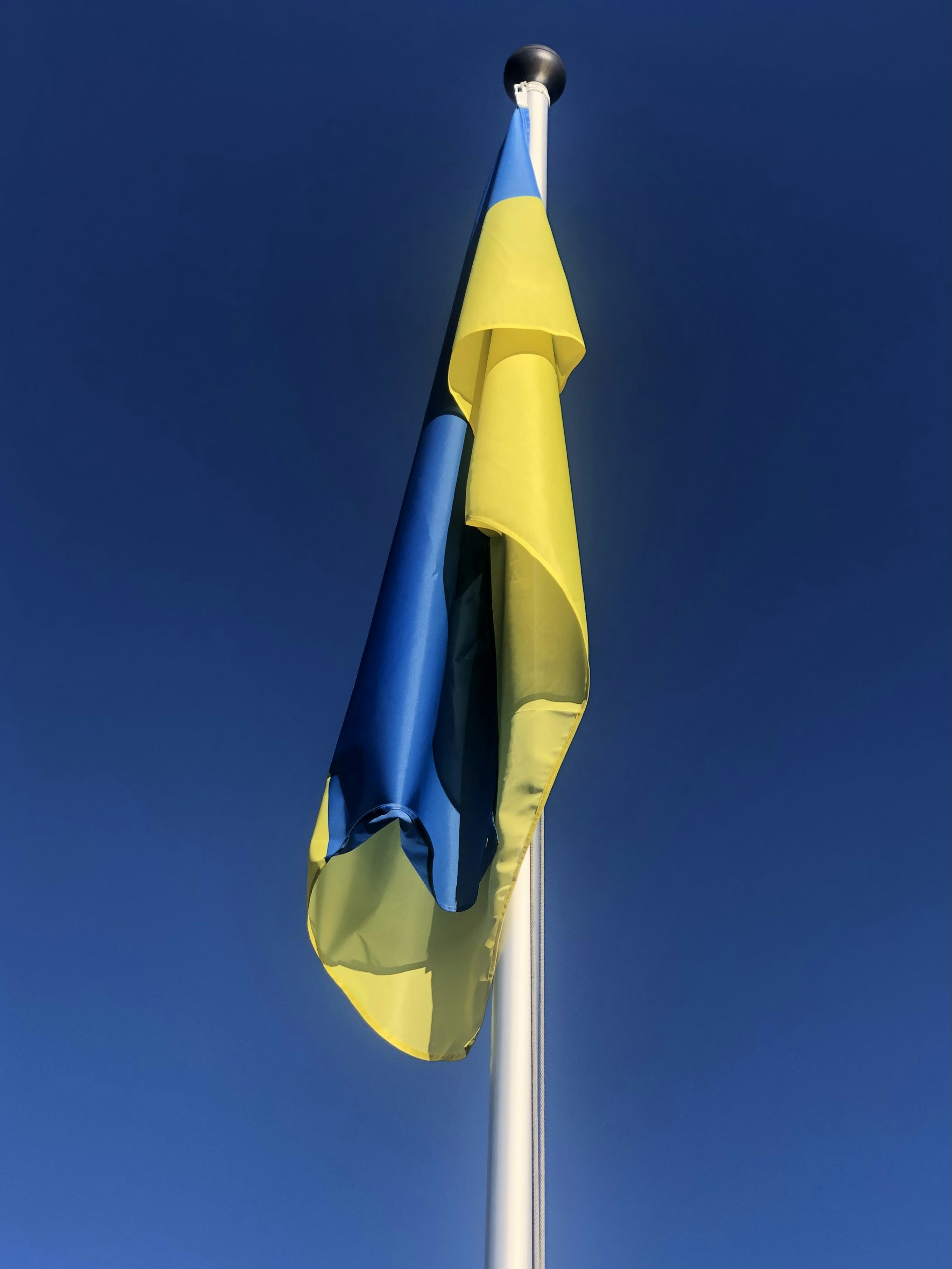 Ukrainian flag waving proudly against a bright blue sky, showcasing its vibrant colors and fabric texture.