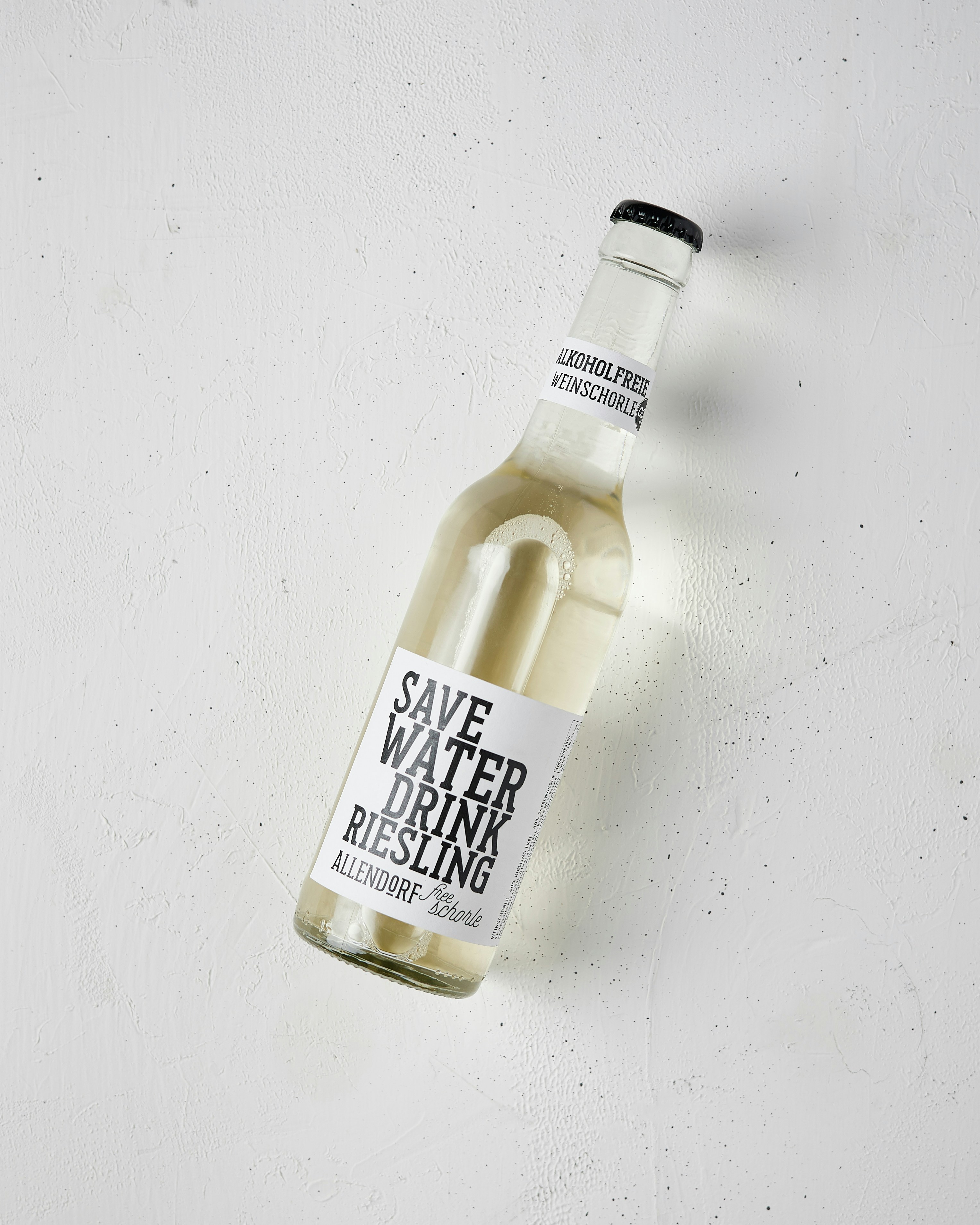 Bottle of Riesling wine with a playful slogan on its label, set against a neutral background. The design emphasizes a sustainable message.