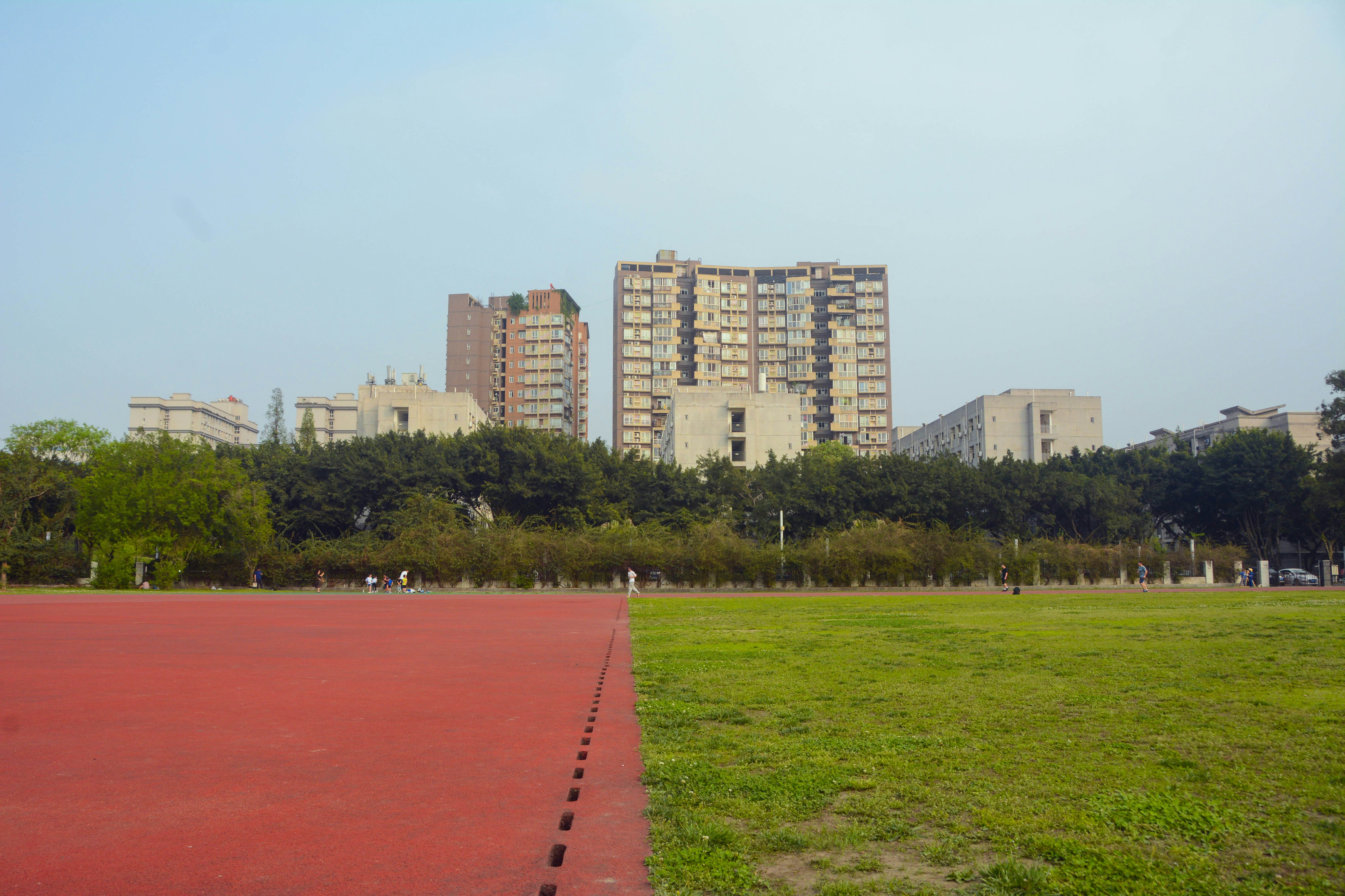 A vibrant red track juxtaposed against lush greenery and urban buildings, showcasing the blend of nature and city life.