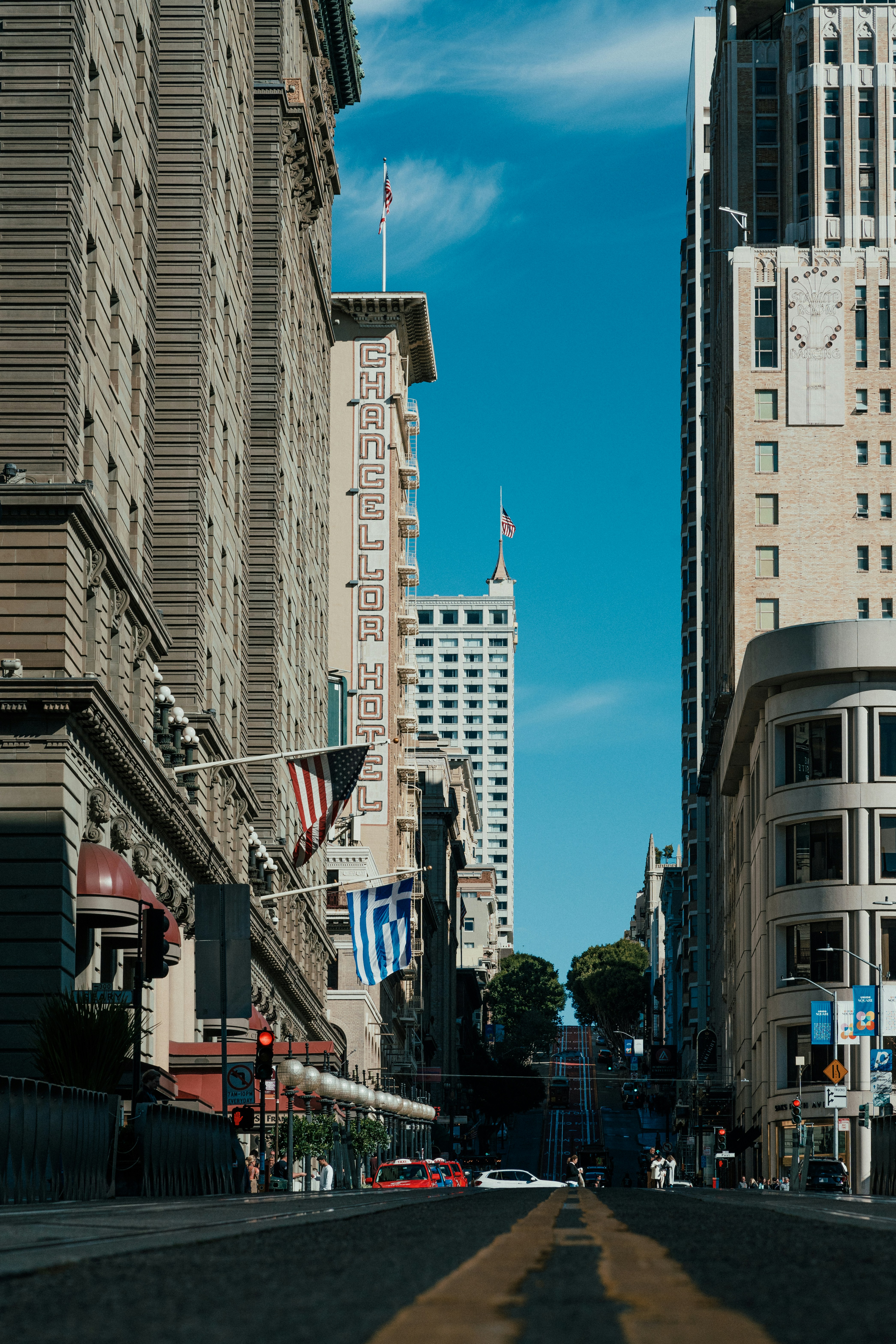 Historic architecture flanks a bustling street, with the Chancellor Hotel sign prominently displayed against a clear blue sky.
