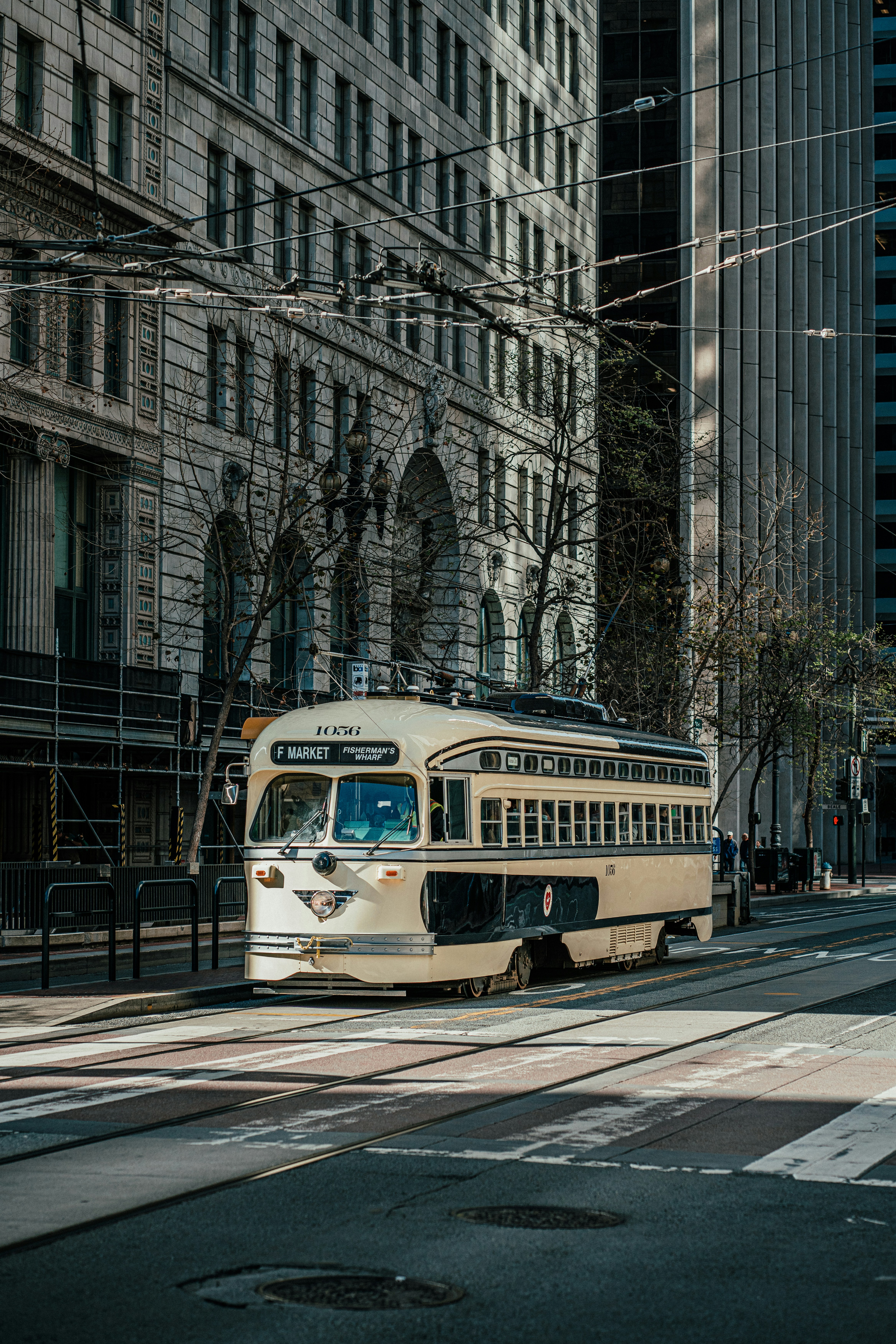 Old tram in San Francisco | a white bus driving down a street next to tall buildings