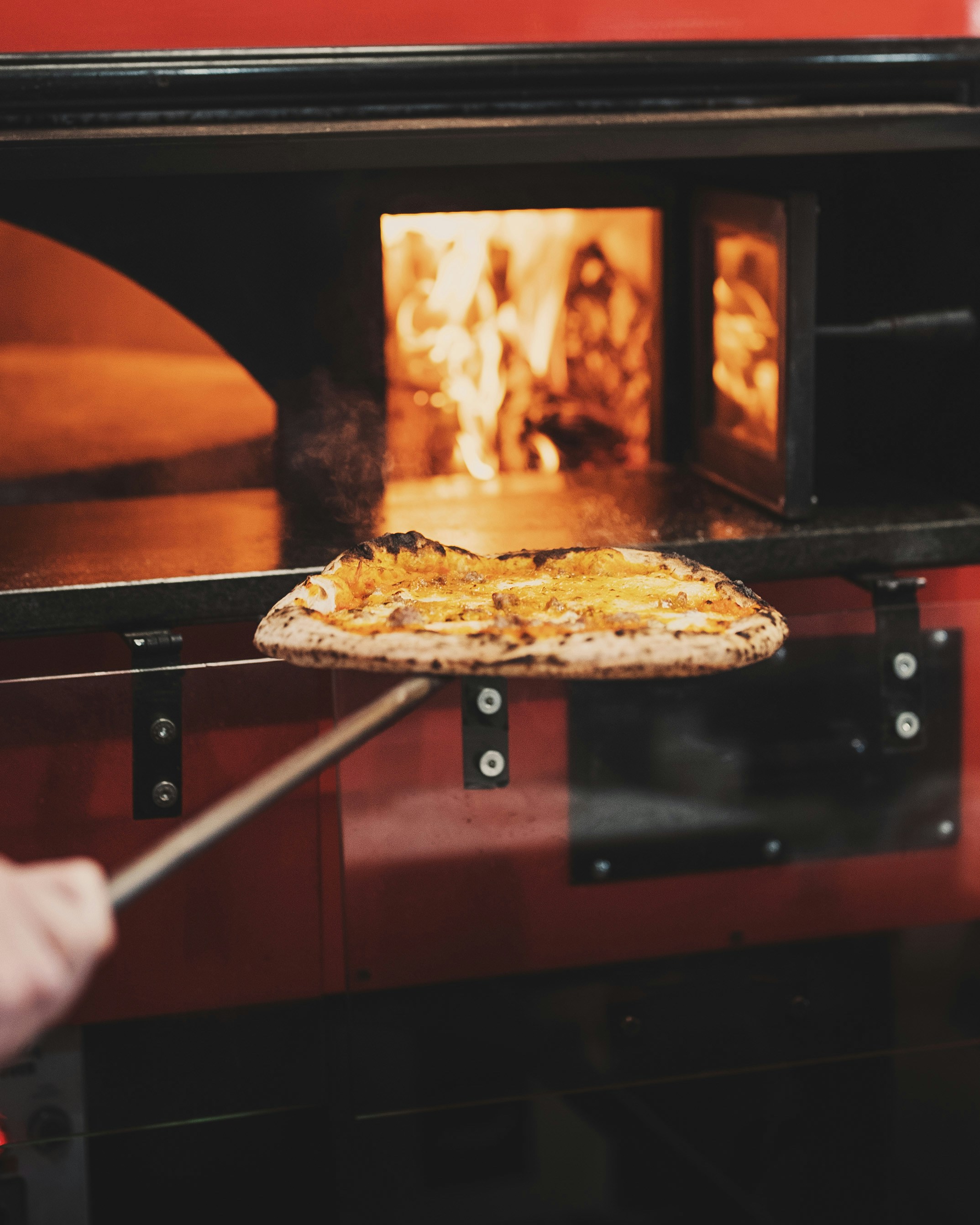 Pizza on a Flame: Fire-Kissed Bake Beneath a Conveyor Oven