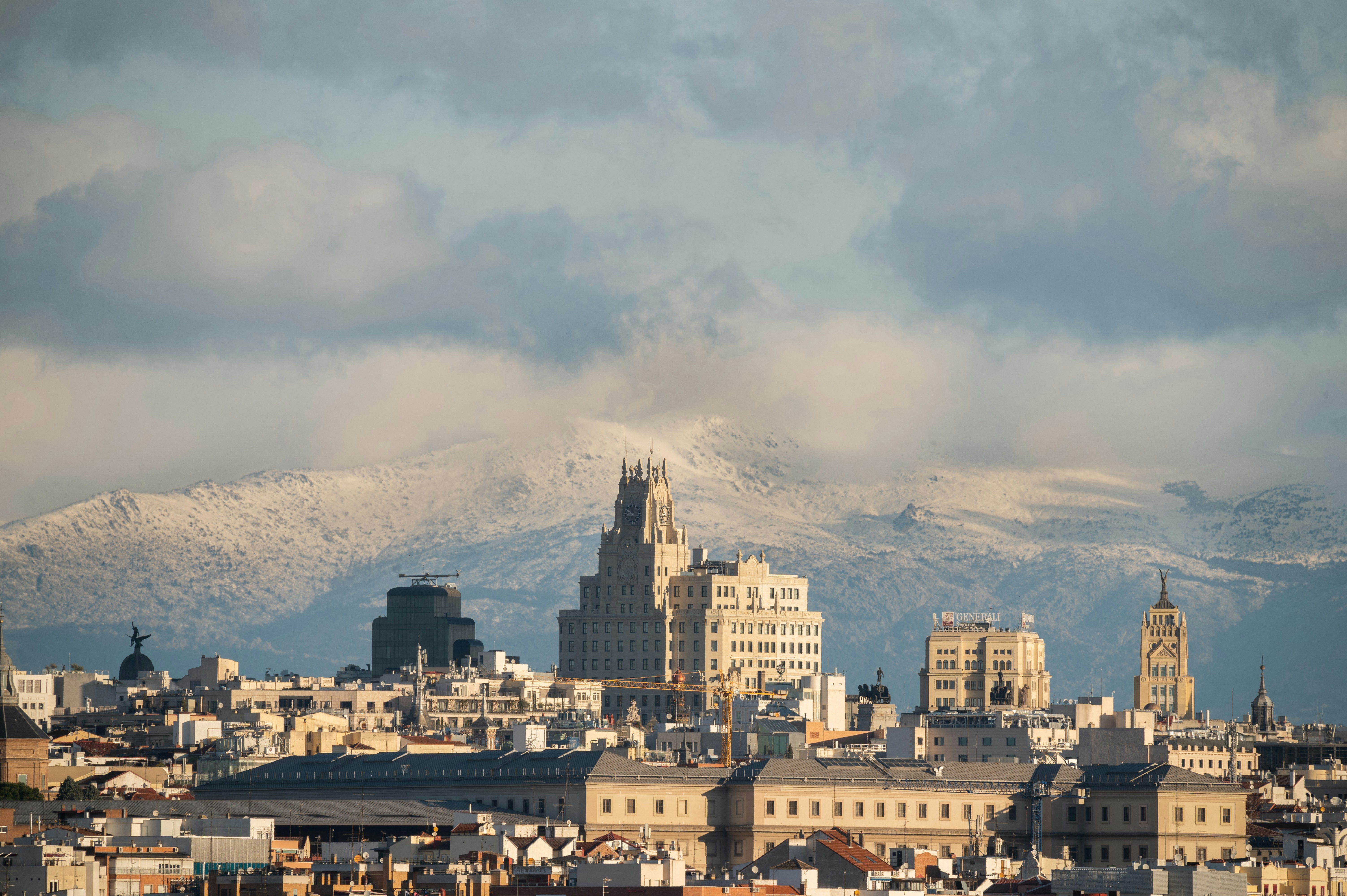 Alpine Edge: Sunlit City Crowned by Snow-Kissed Peaks