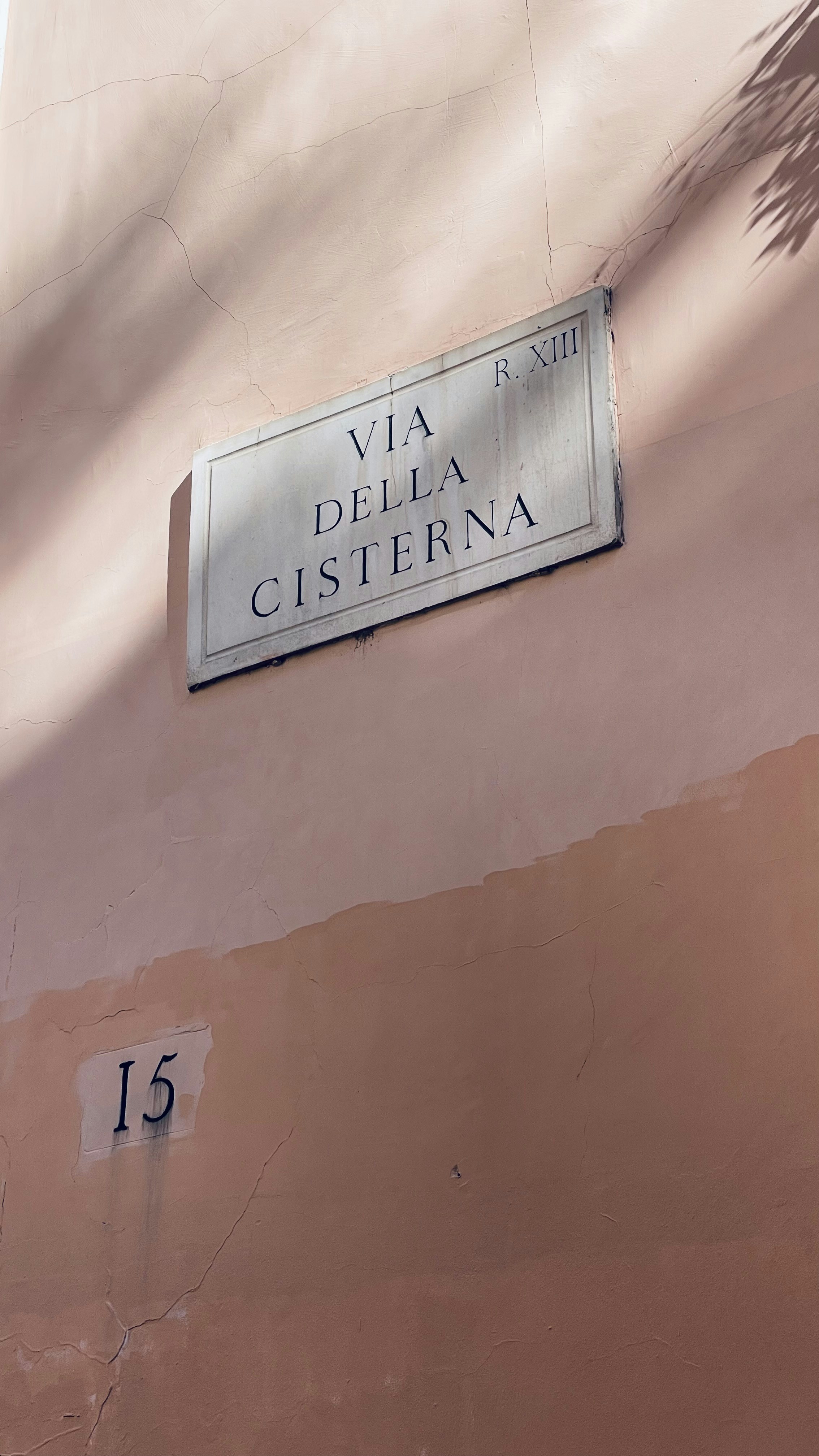 Weathered street sign reading 'Via della Cisterna' mounted on a pastel wall, capturing the charm of a historic neighborhood.