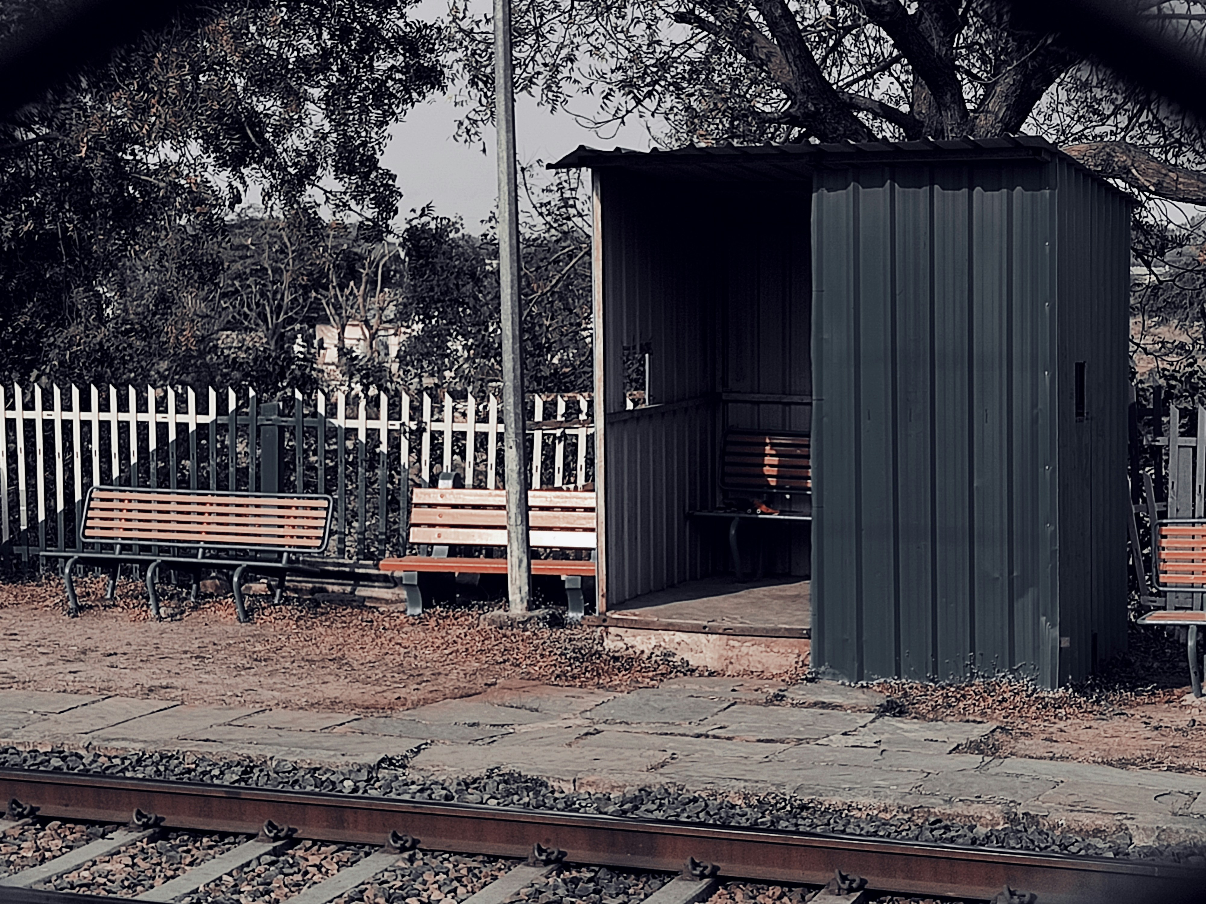 A couple of benches sitting next to a train track photo – Free ...