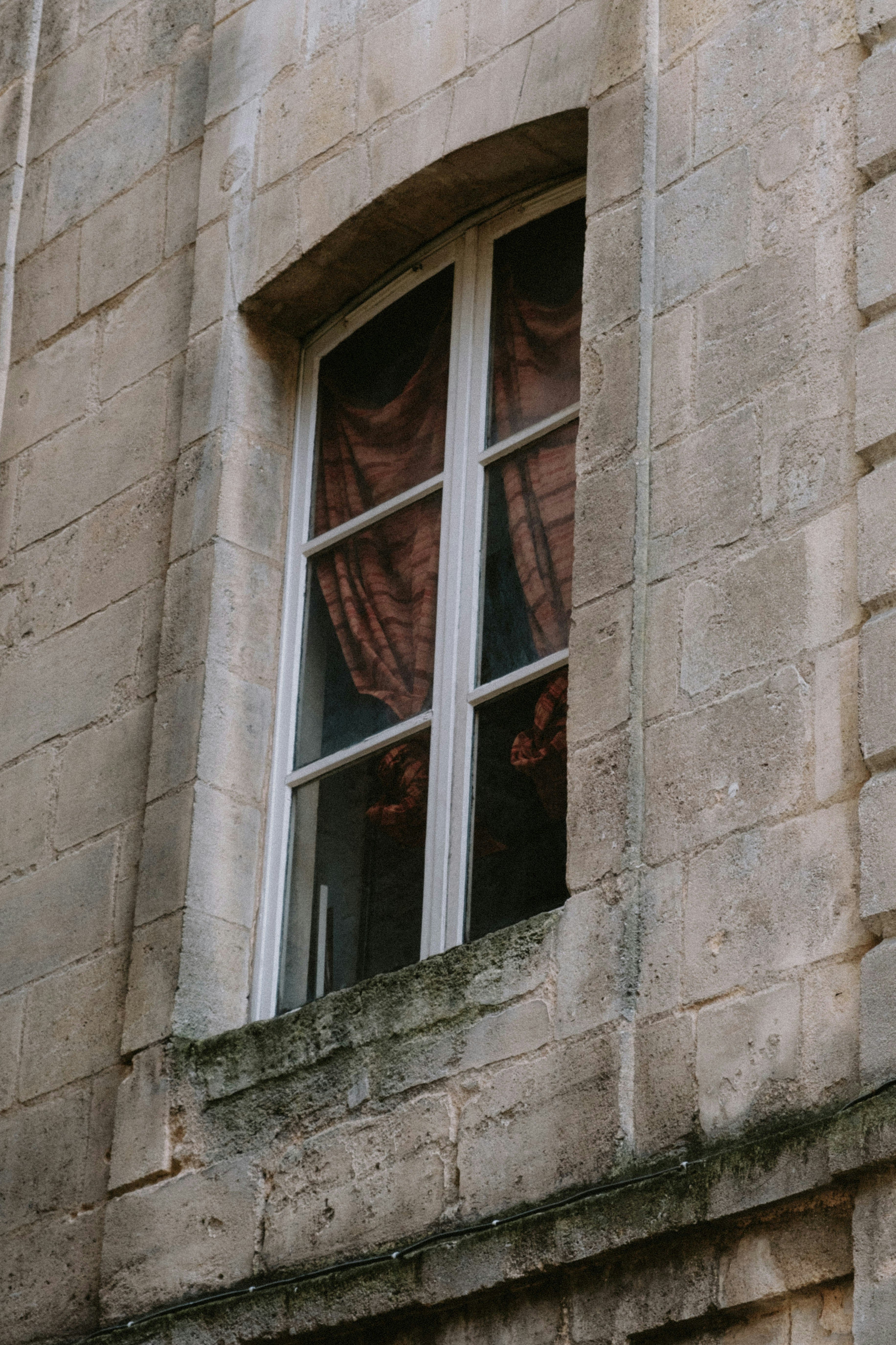 a window with a curtain and a clock on it