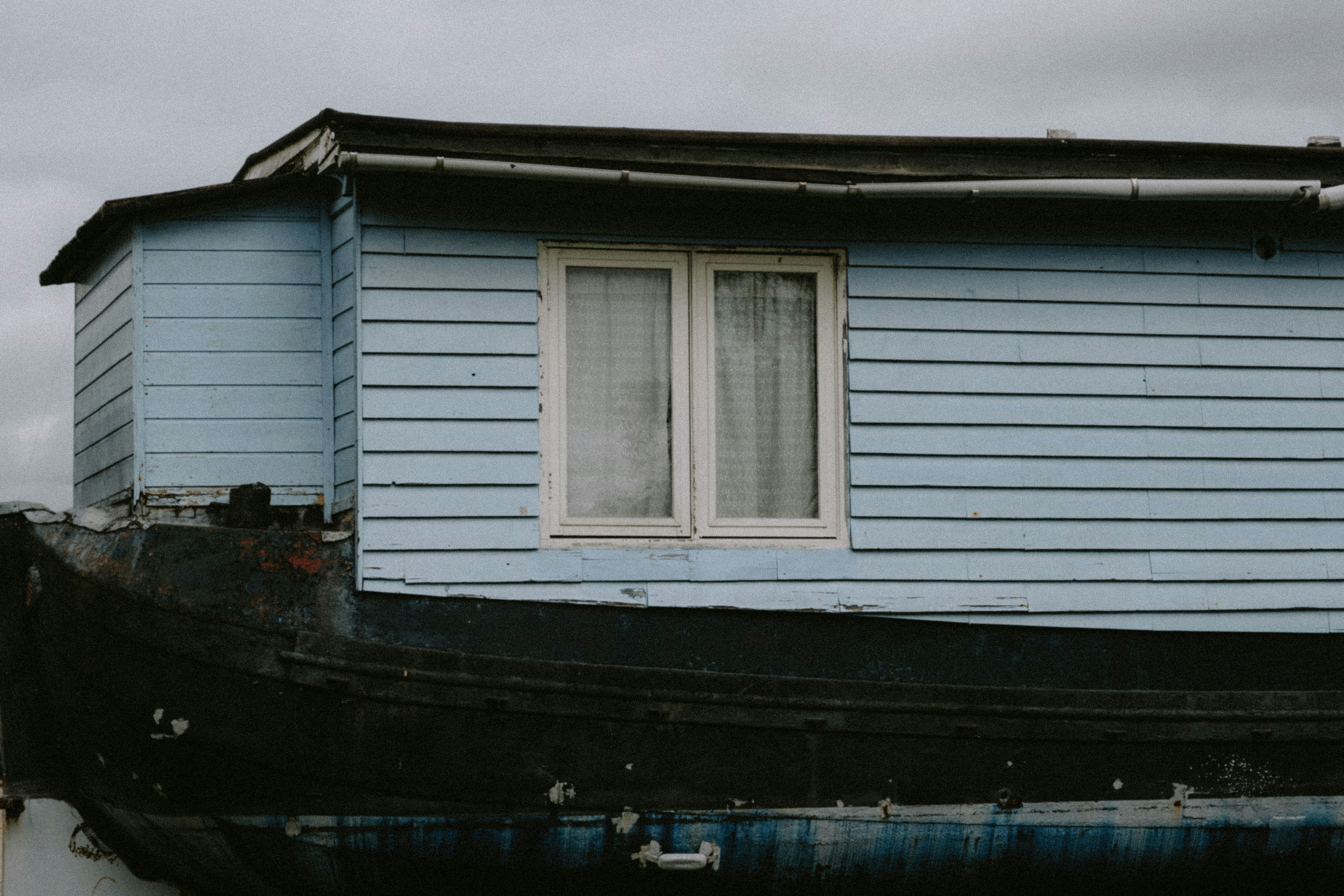 Blue Boat House Window: Quiet Detail on a Weathered Hull