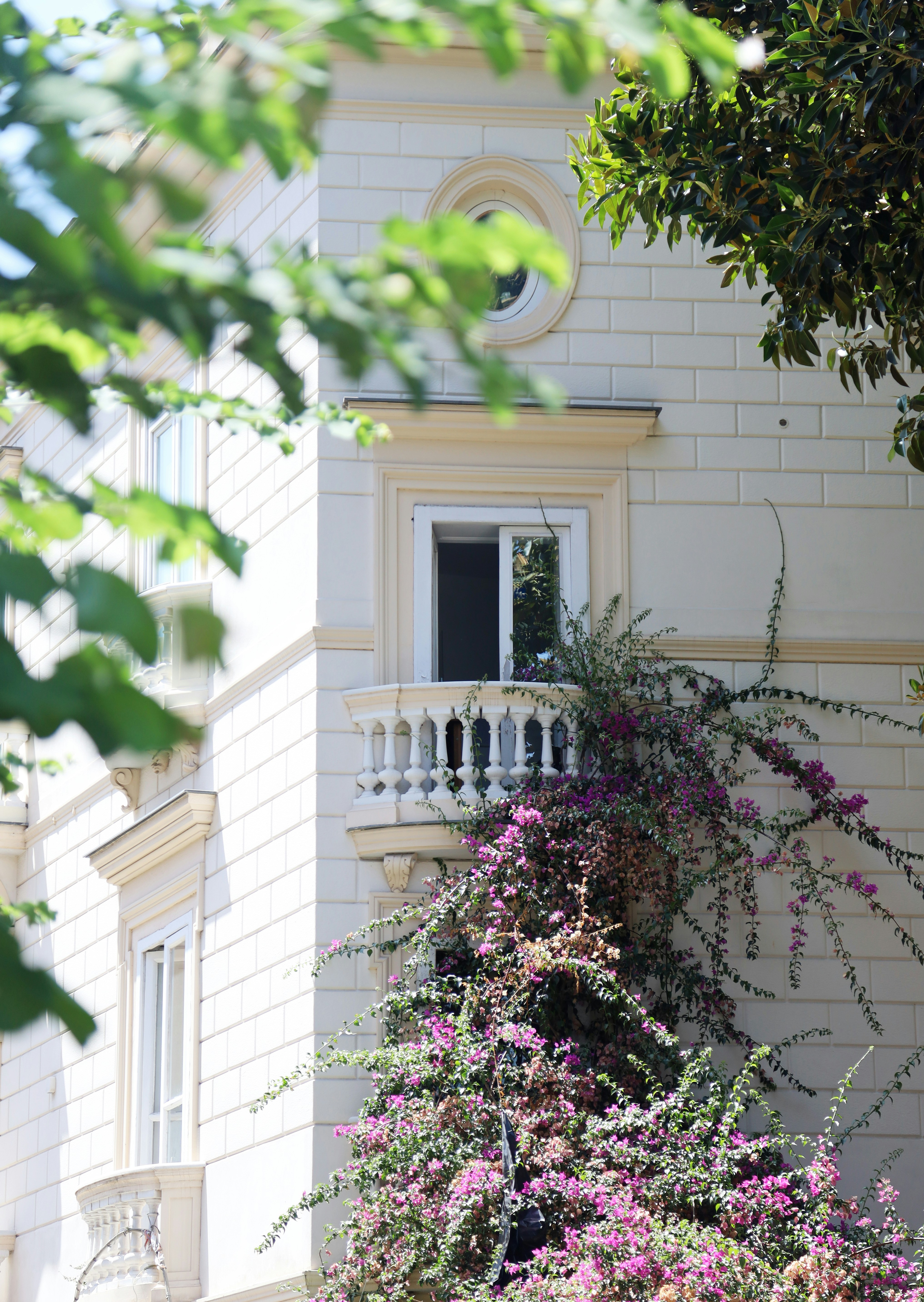 A charming balcony adorned with vibrant bougainvillea, showcasing a blend of nature and architecture in a sunlit urban setting.