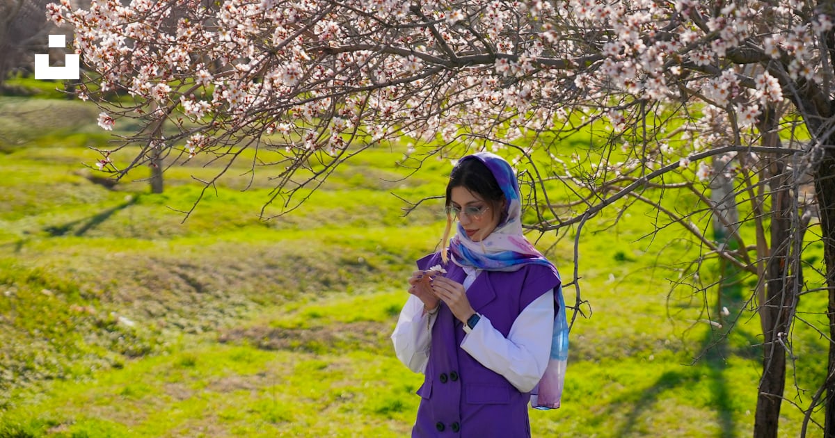 Una Mujer Parada Frente A Un árbol Con Un Teléfono Celular Foto