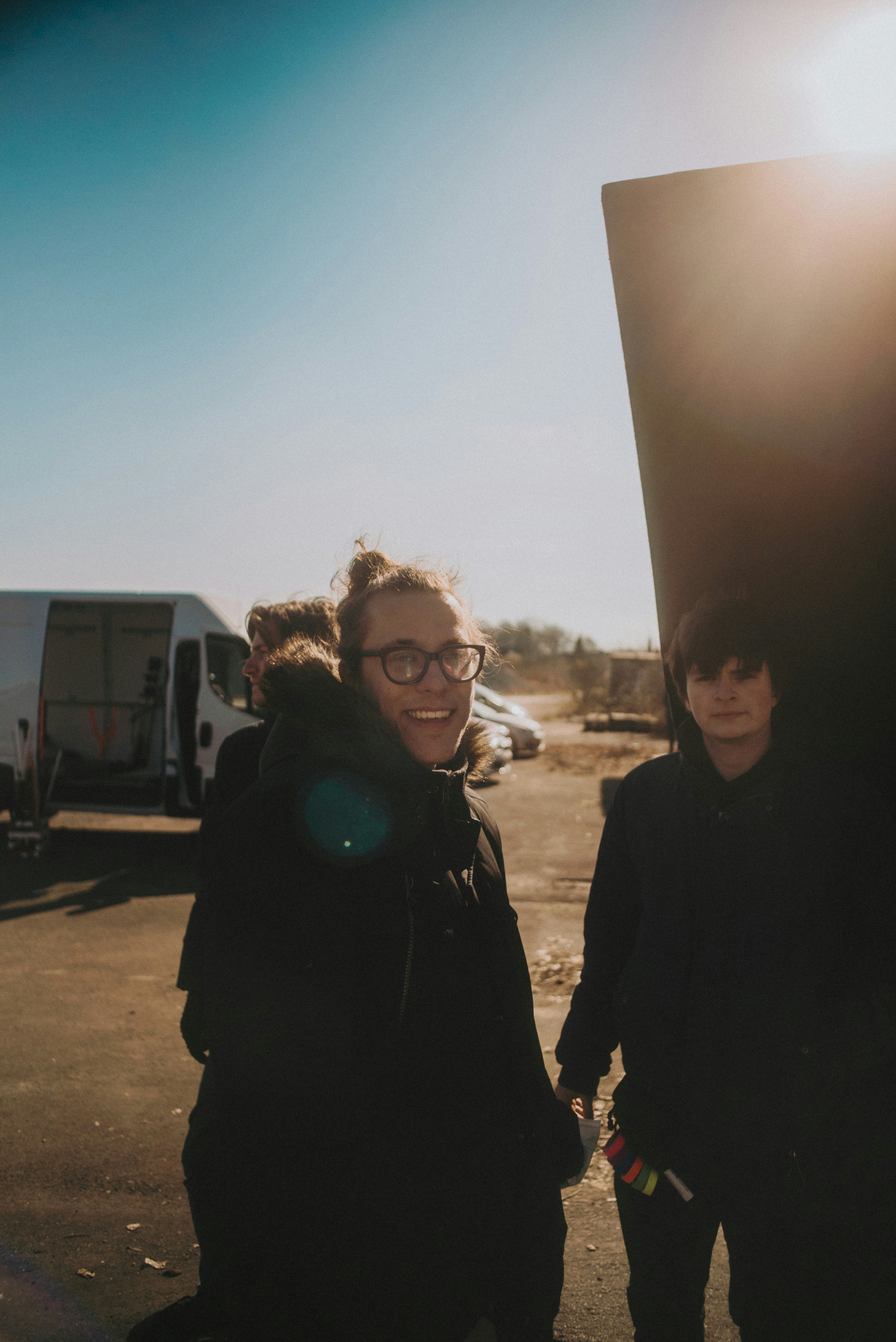 Two individuals share a moment during a film shoot, illuminated by bright sunlight. The scene captures the collaborative spirit of production.