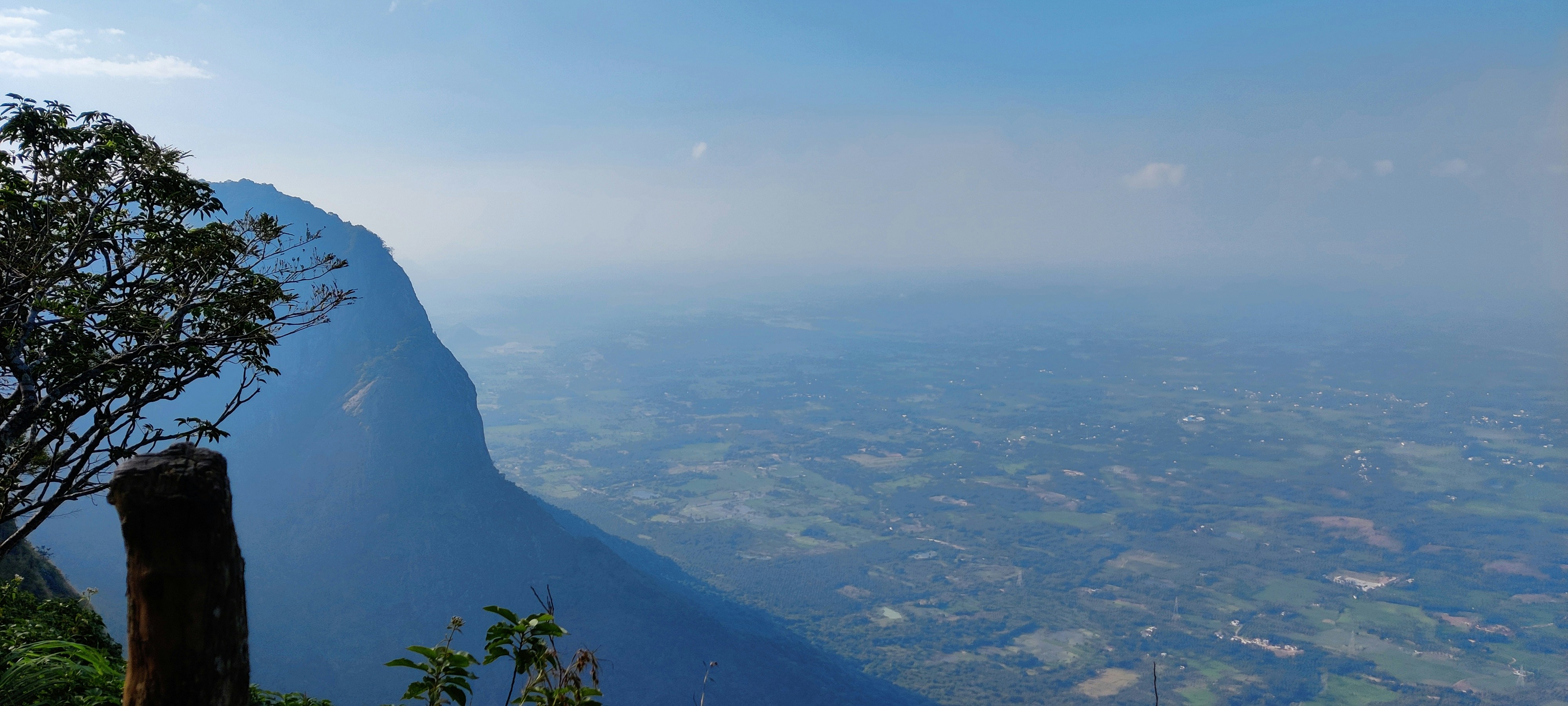 Expansive view from a mountain summit, showcasing rolling landscapes and distant horizons under a clear sky.