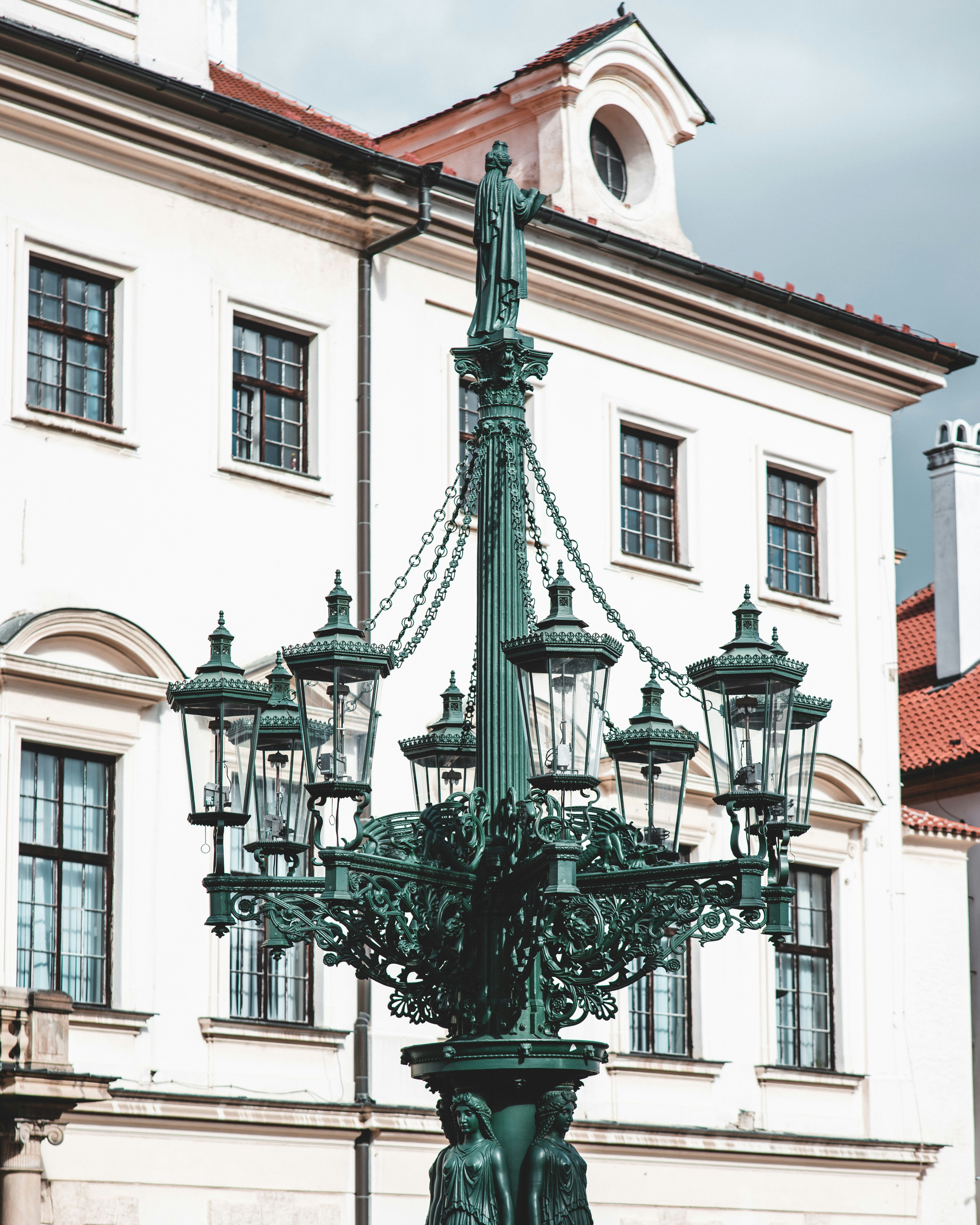 A green lamp post in front of a white building photo – Free Prague ...